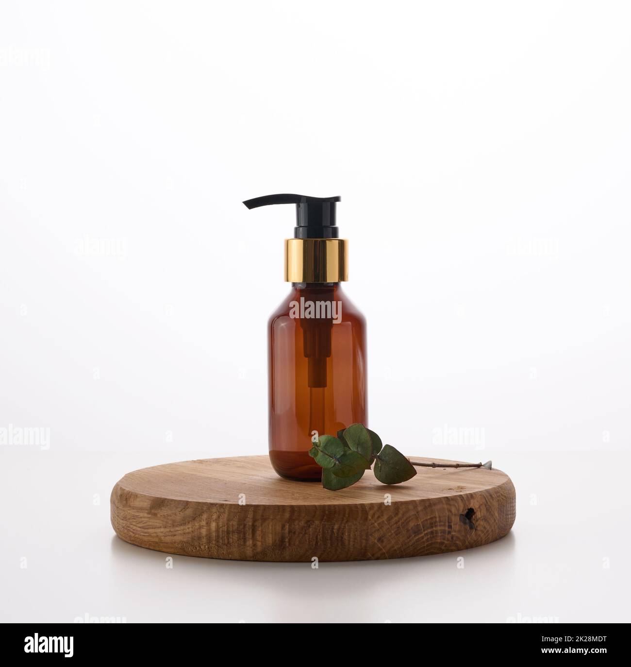 Brown glass bottle with black pump of cosmetic products on white table ...