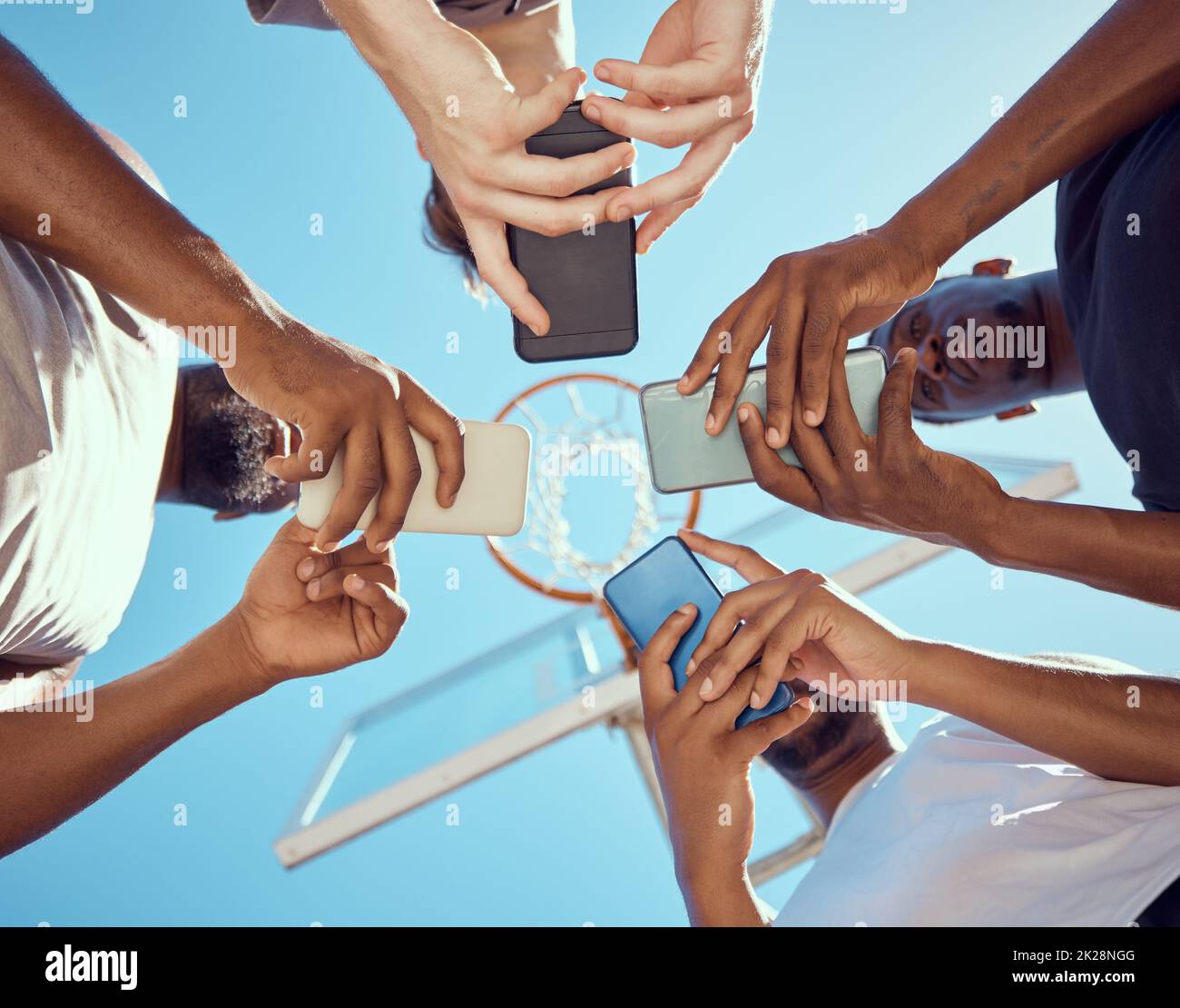 Basketball team in a circle with phone networking on social media while standing on a court ...