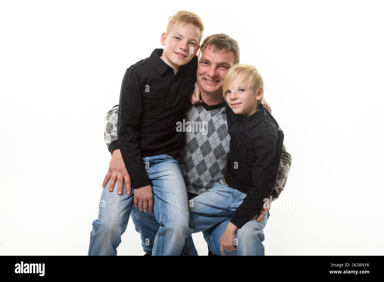 Half Length Portrait Of A Father And Two Sons In Casual Clothes On A