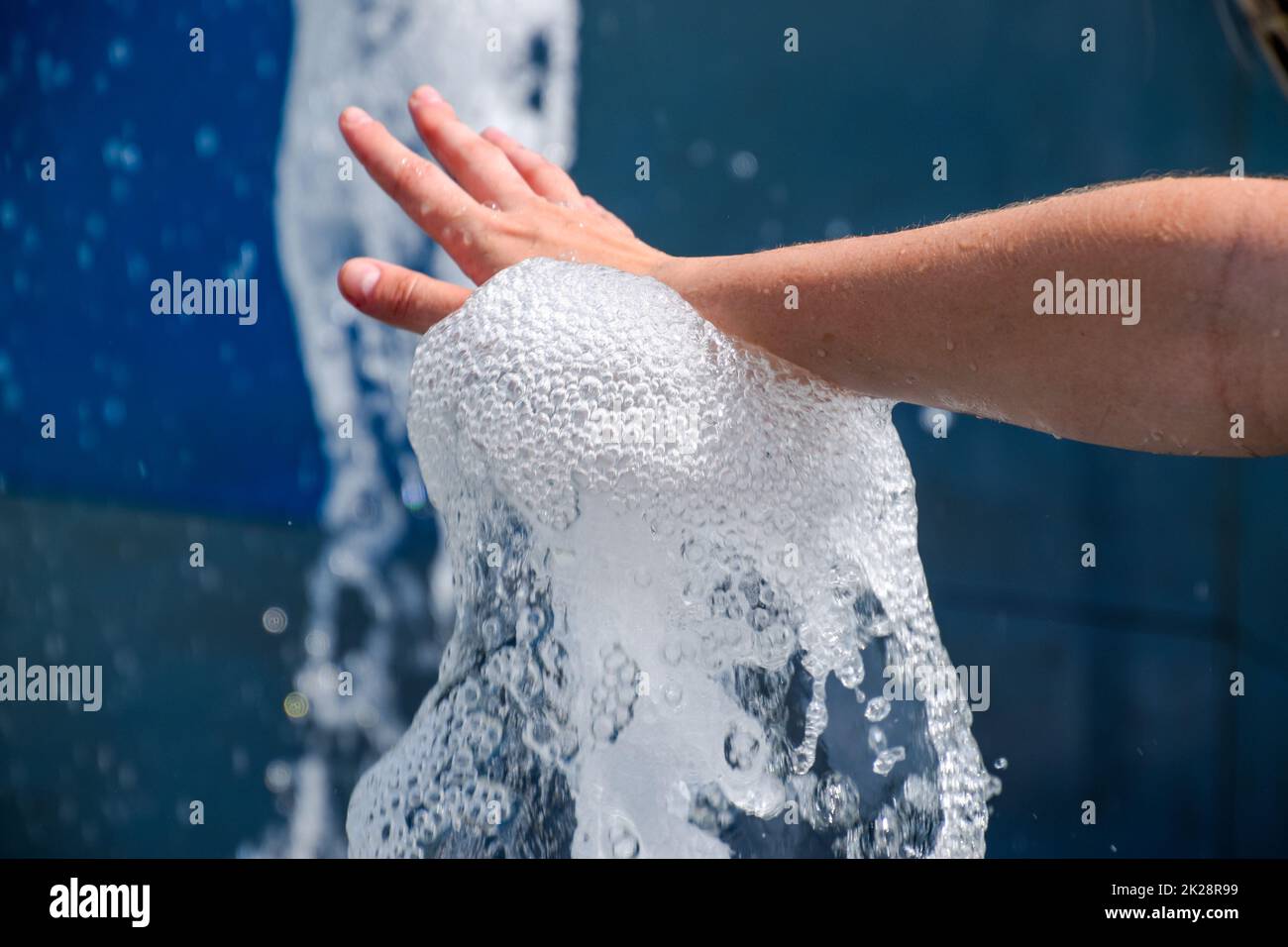 Hand touch the fountain. A stream of water from the fountain is touched ...
