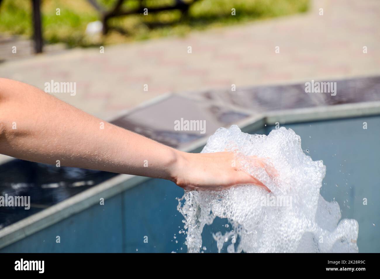 Hand touch the fountain. A stream of water from the fountain is touched ...