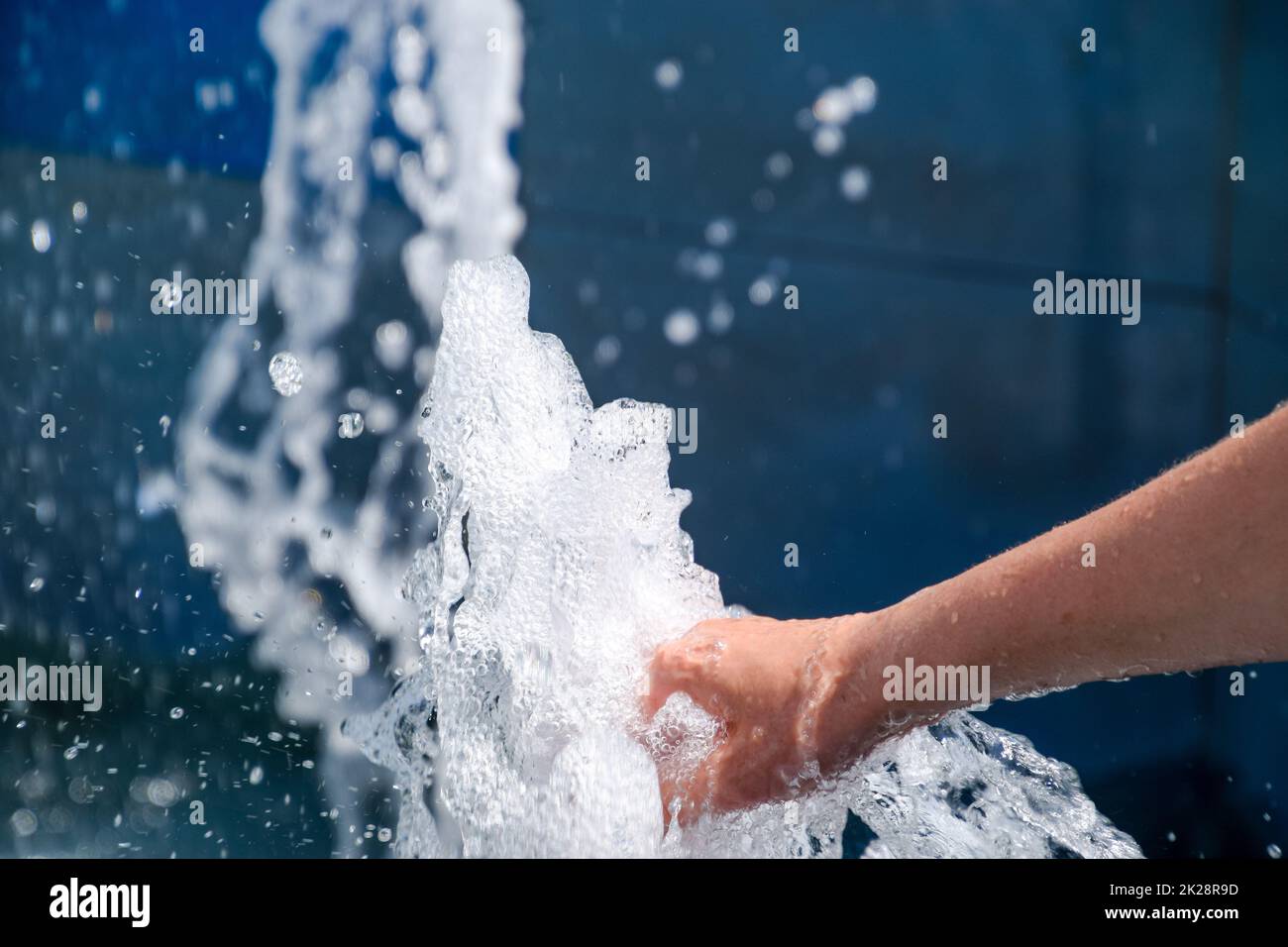 Hand touch the fountain. A stream of water from the fountain is touched ...