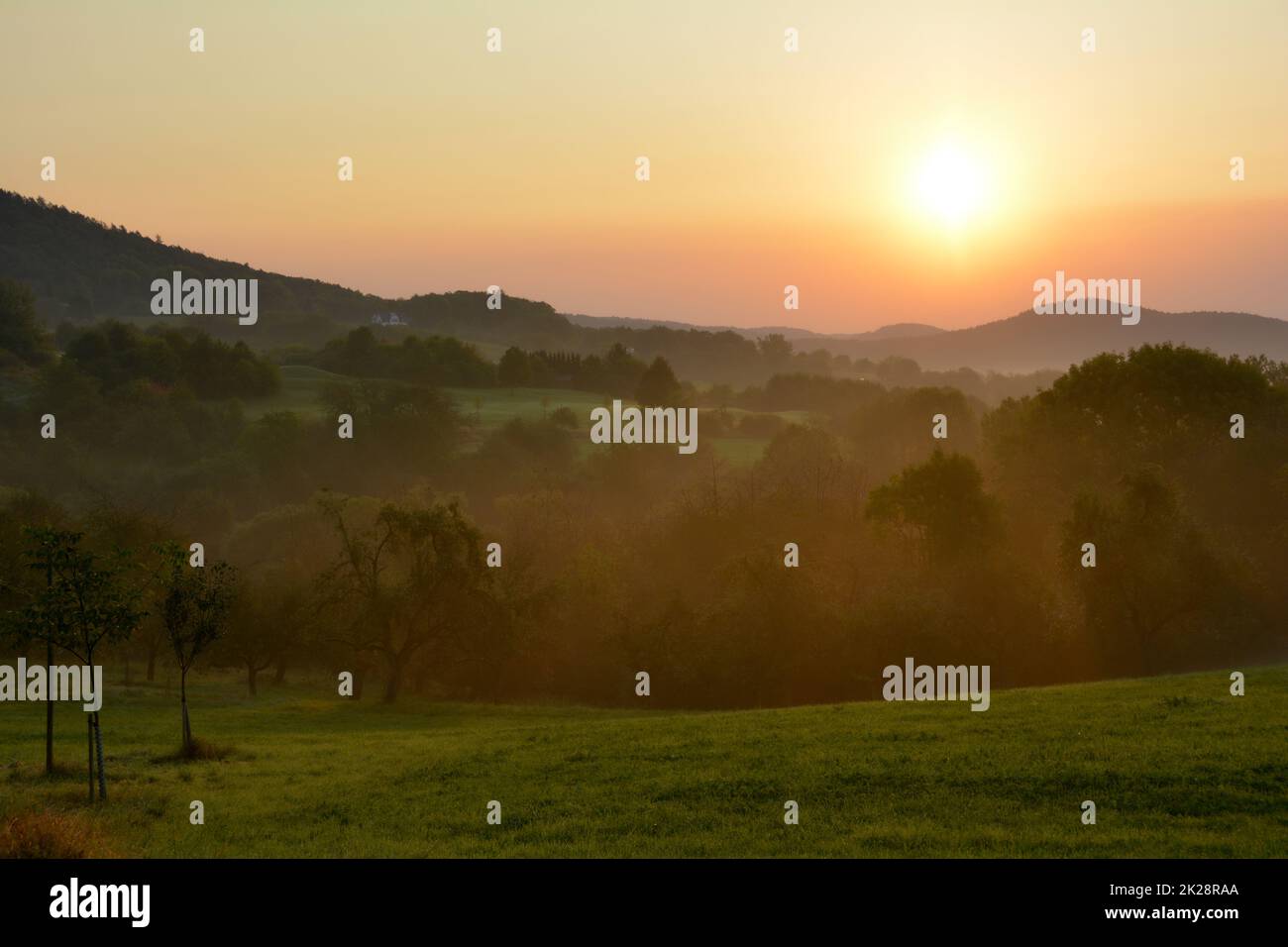 Sun rises over a landscape with morning fog Stock Photo - Alamy
