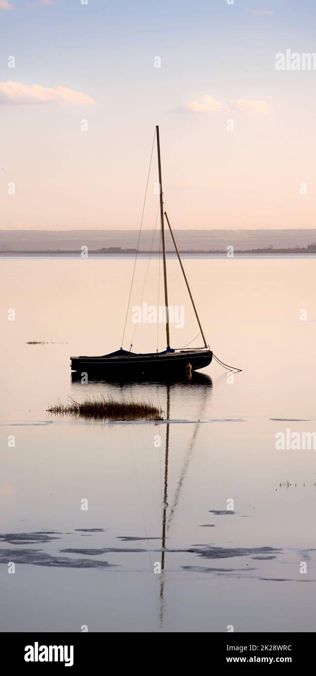 Upright panorama of small dinghy in early morning light on river ...