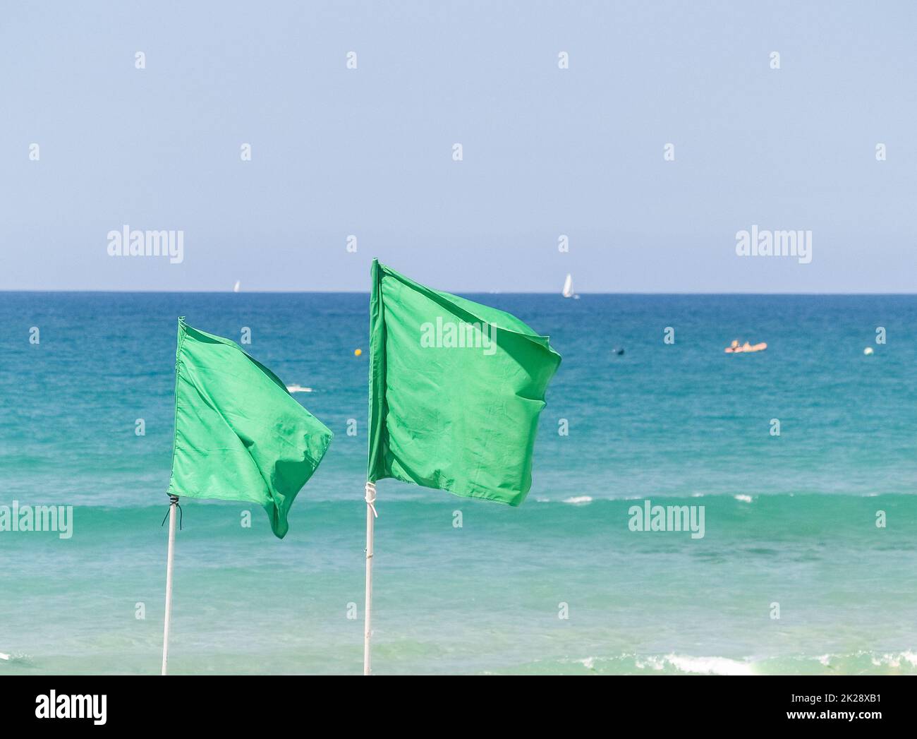 Two Green flags in defocused coastal background Stock Photo - Alamy