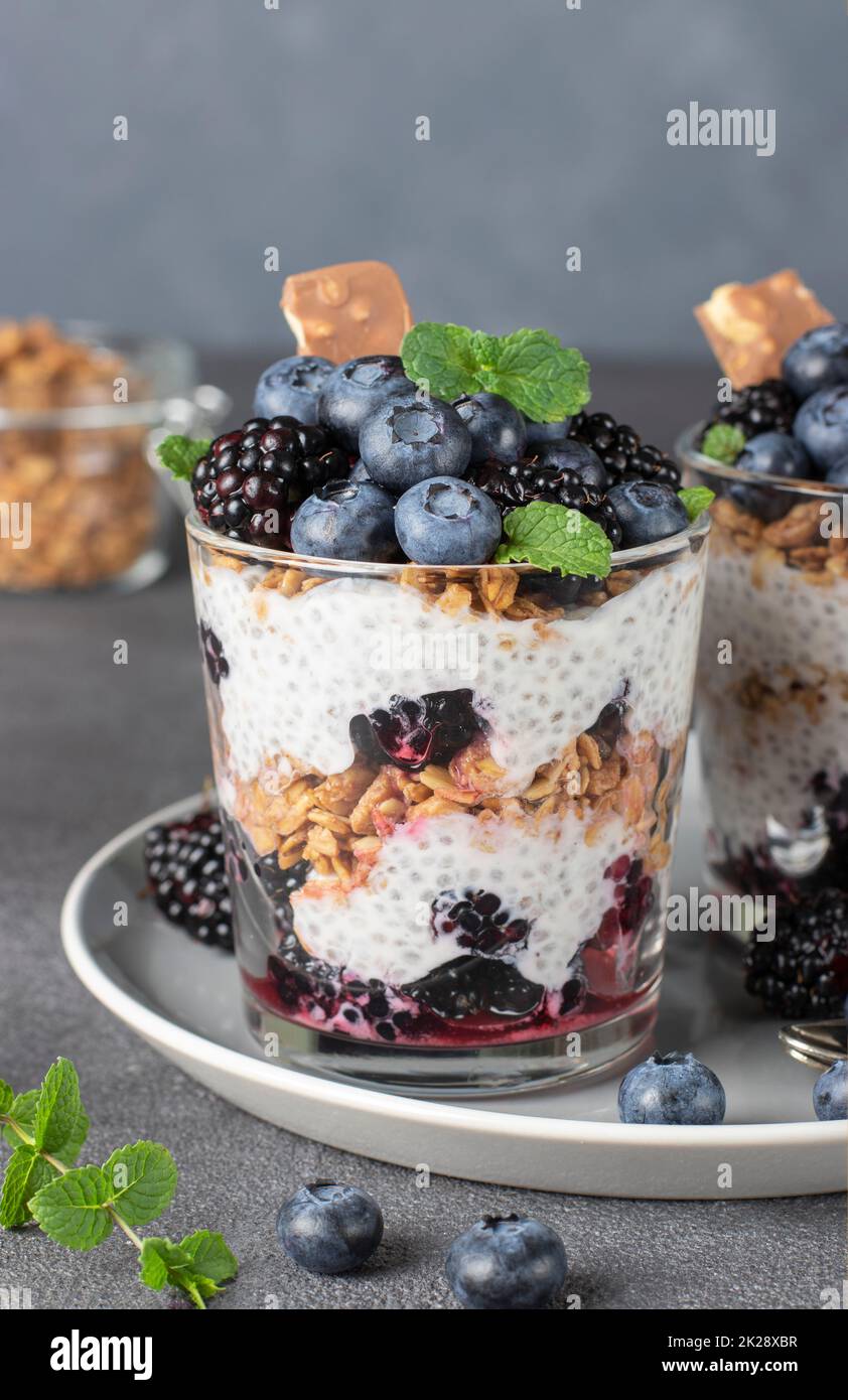 Chia pudding with blueberry and blackberry in two glass on plate on ...