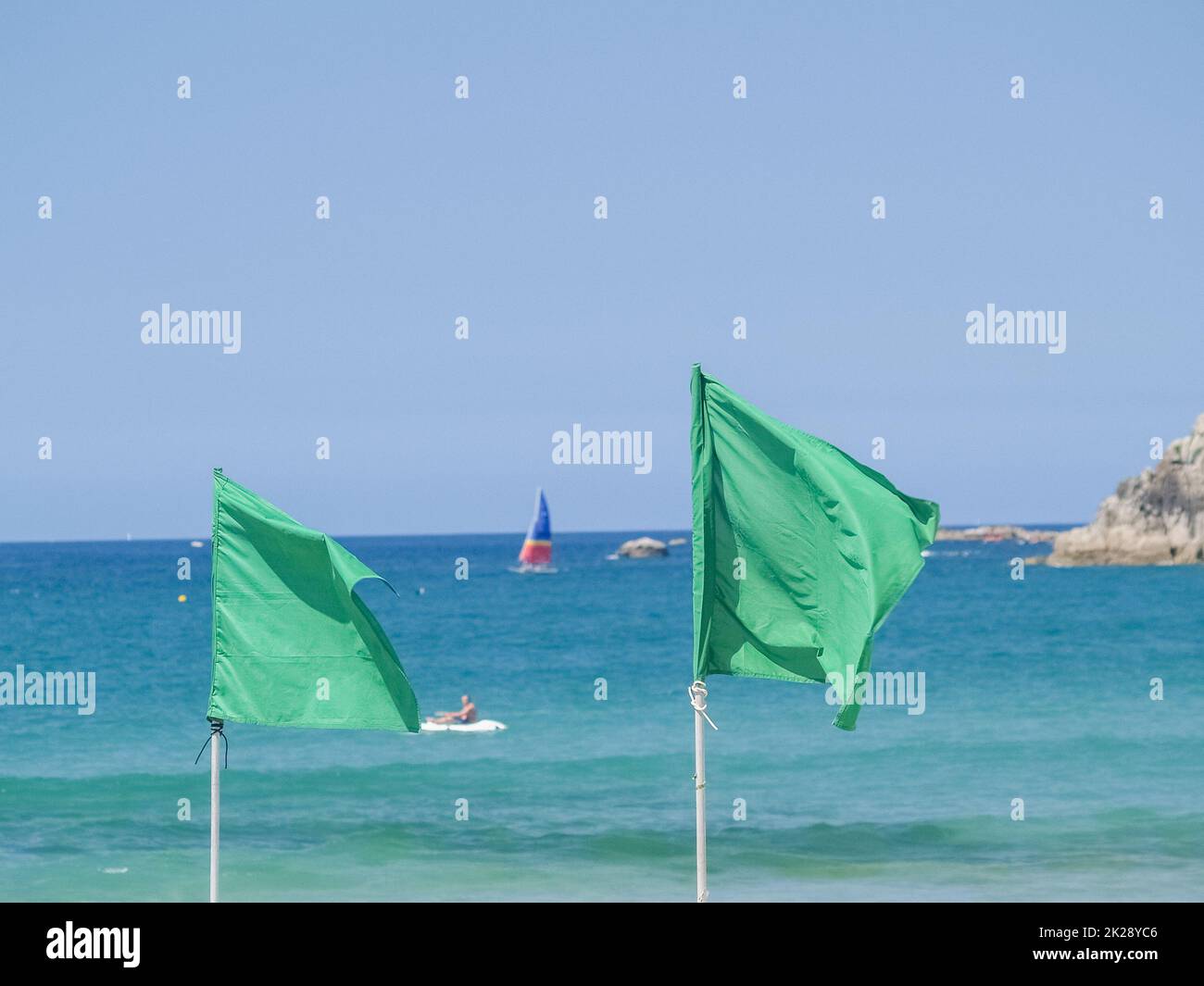 Two Green flags in defocused coastal background Stock Photo - Alamy