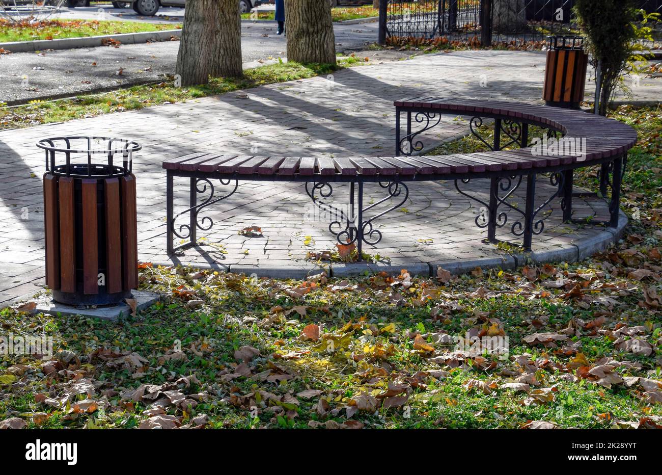bench in an autumn park. Pavement of tiles and garbage can Stock Photo ...