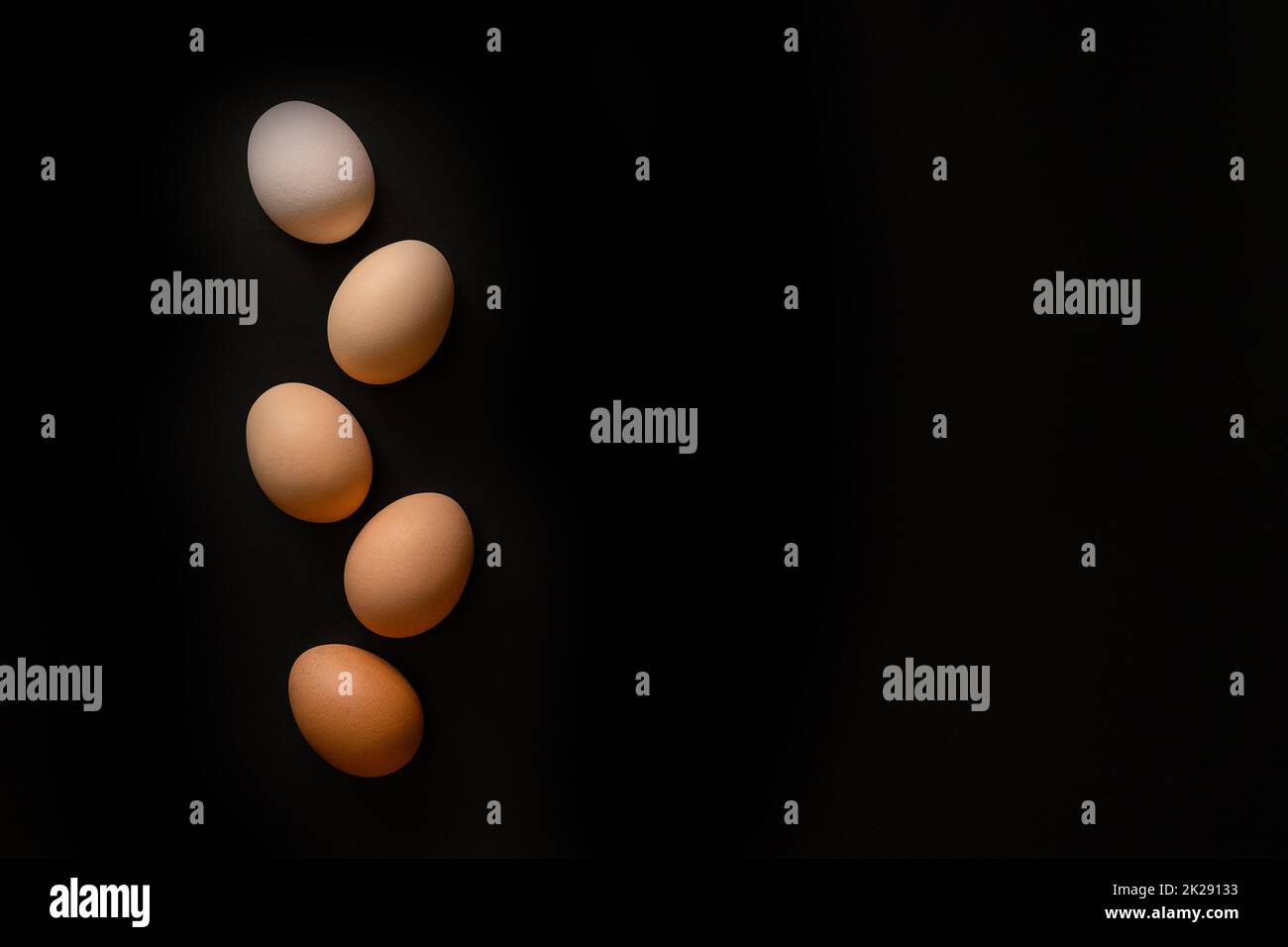 Eggs of different shades on a black background Stock Photo - Alamy
