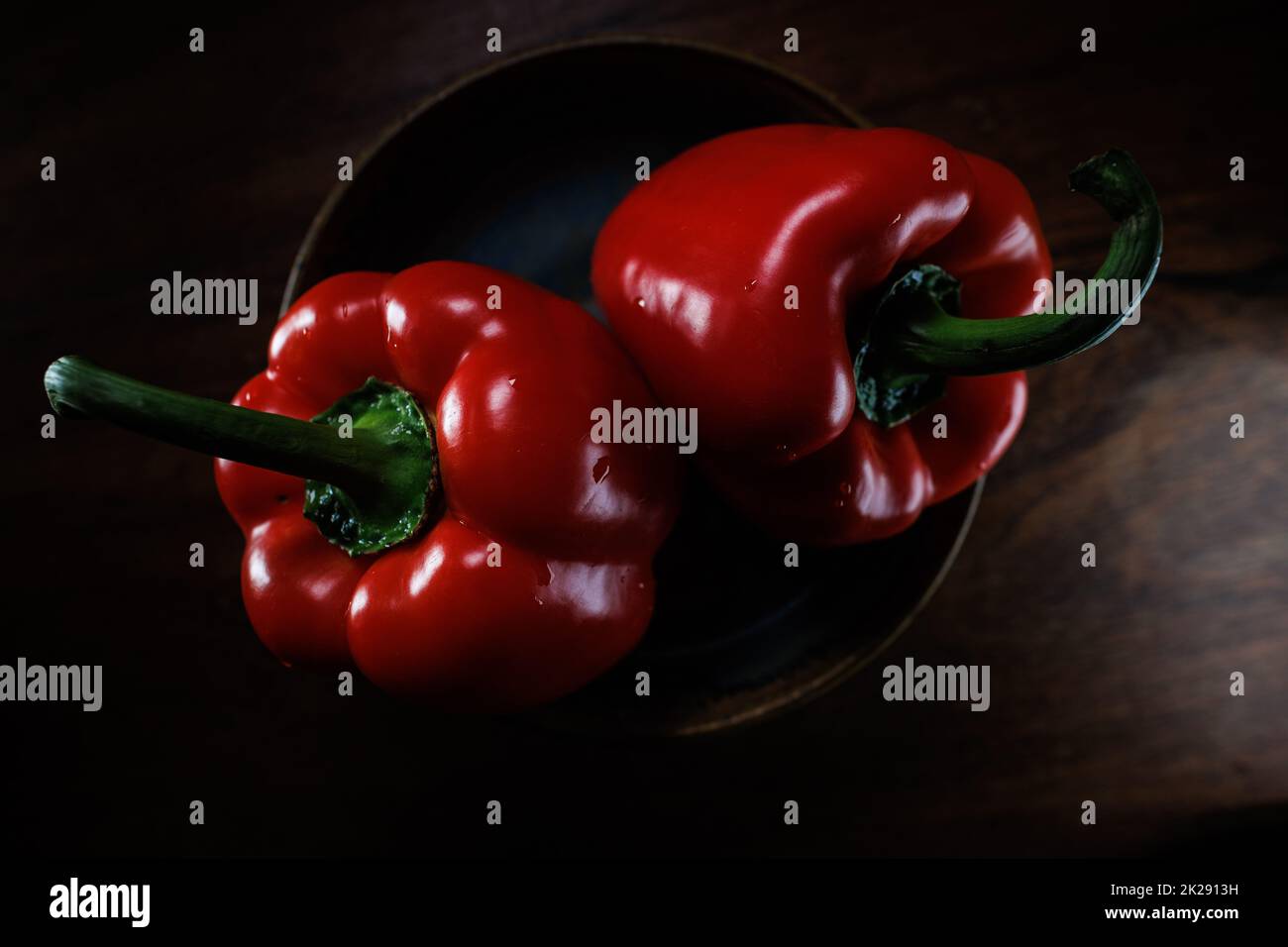 Two red pepper in bowl with dark backround Stock Photo - Alamy