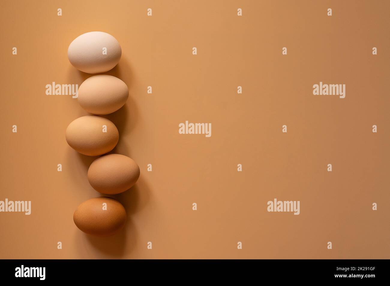Eggs of different shades in balance on a light brown background, top ...