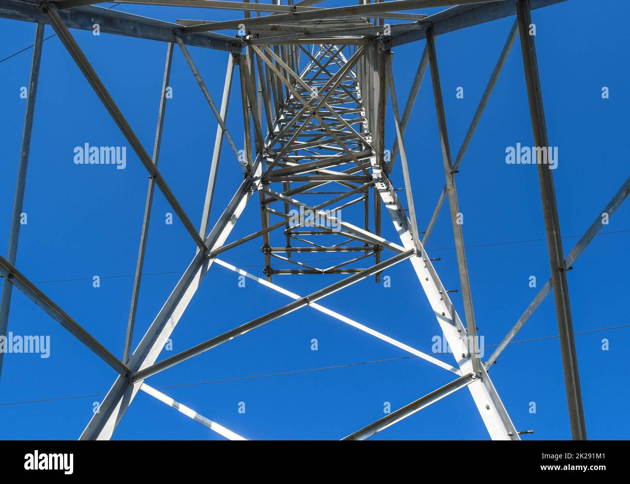 Supports high-voltage power lines against the blue sky. View from the ...