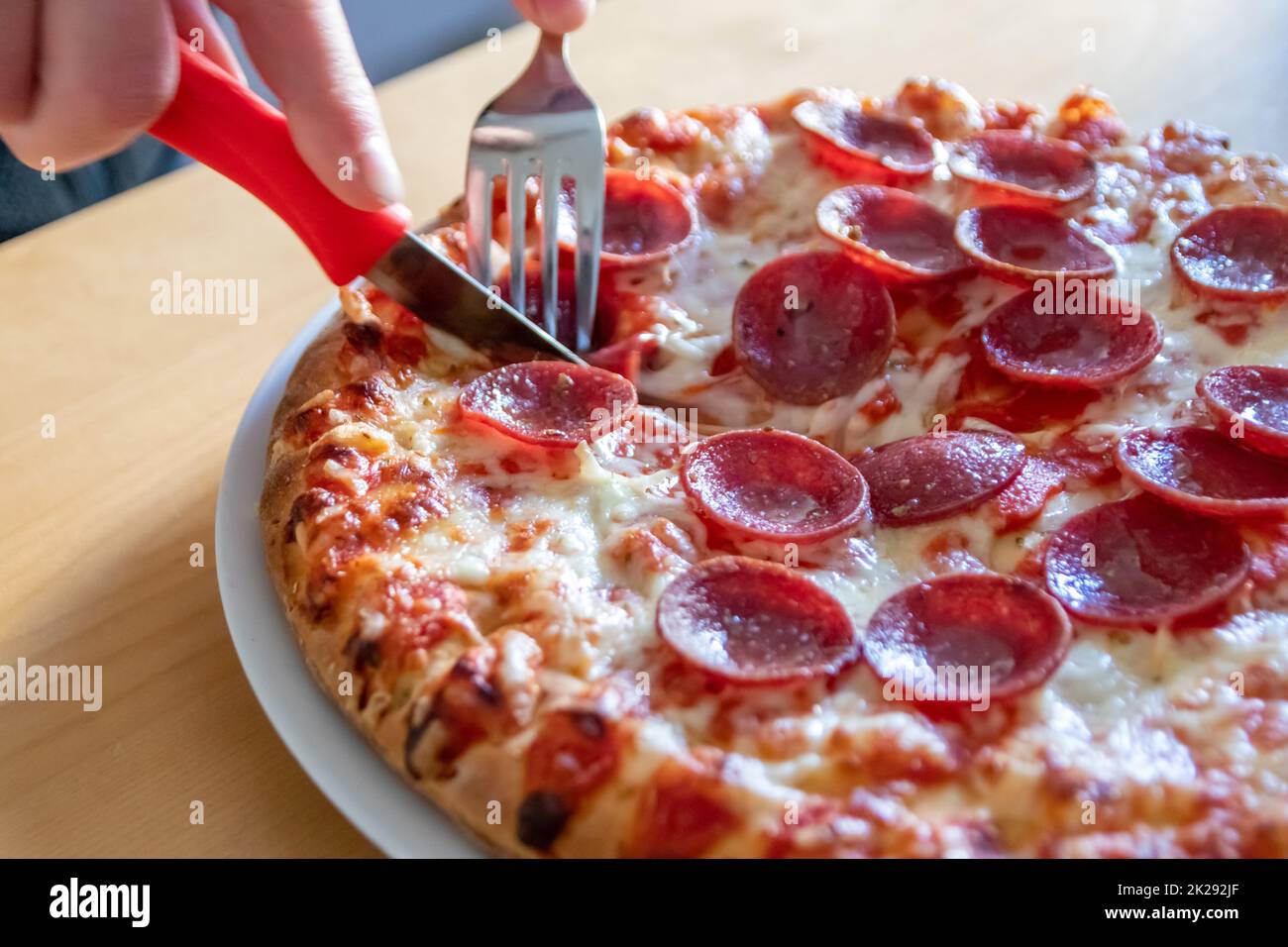 Boy hands cut salami pizza into pieces with fork and knife on pizza ...