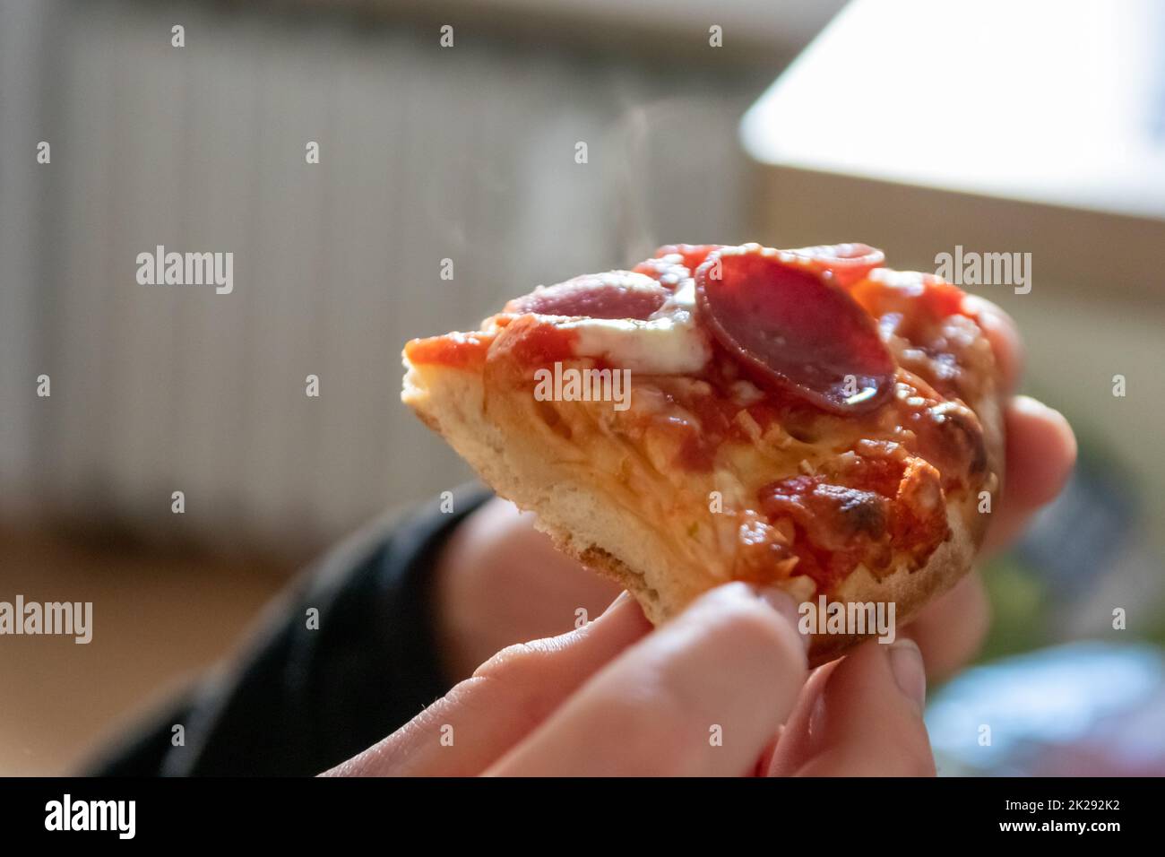 Child hand holding piece of pizza salami with hot steam and delicious ...