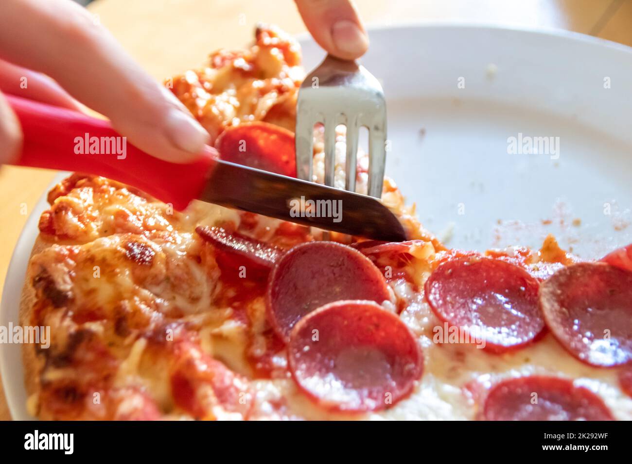 Boy hands cut salami pizza into pieces with fork and knife on pizza ...