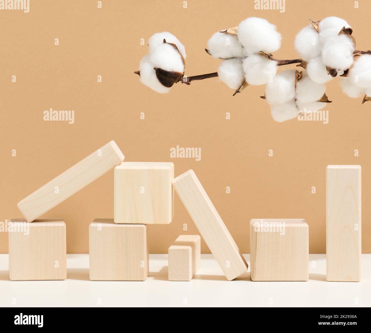 wooden cubes stacked and branches with white cotton flowers on a brown ...