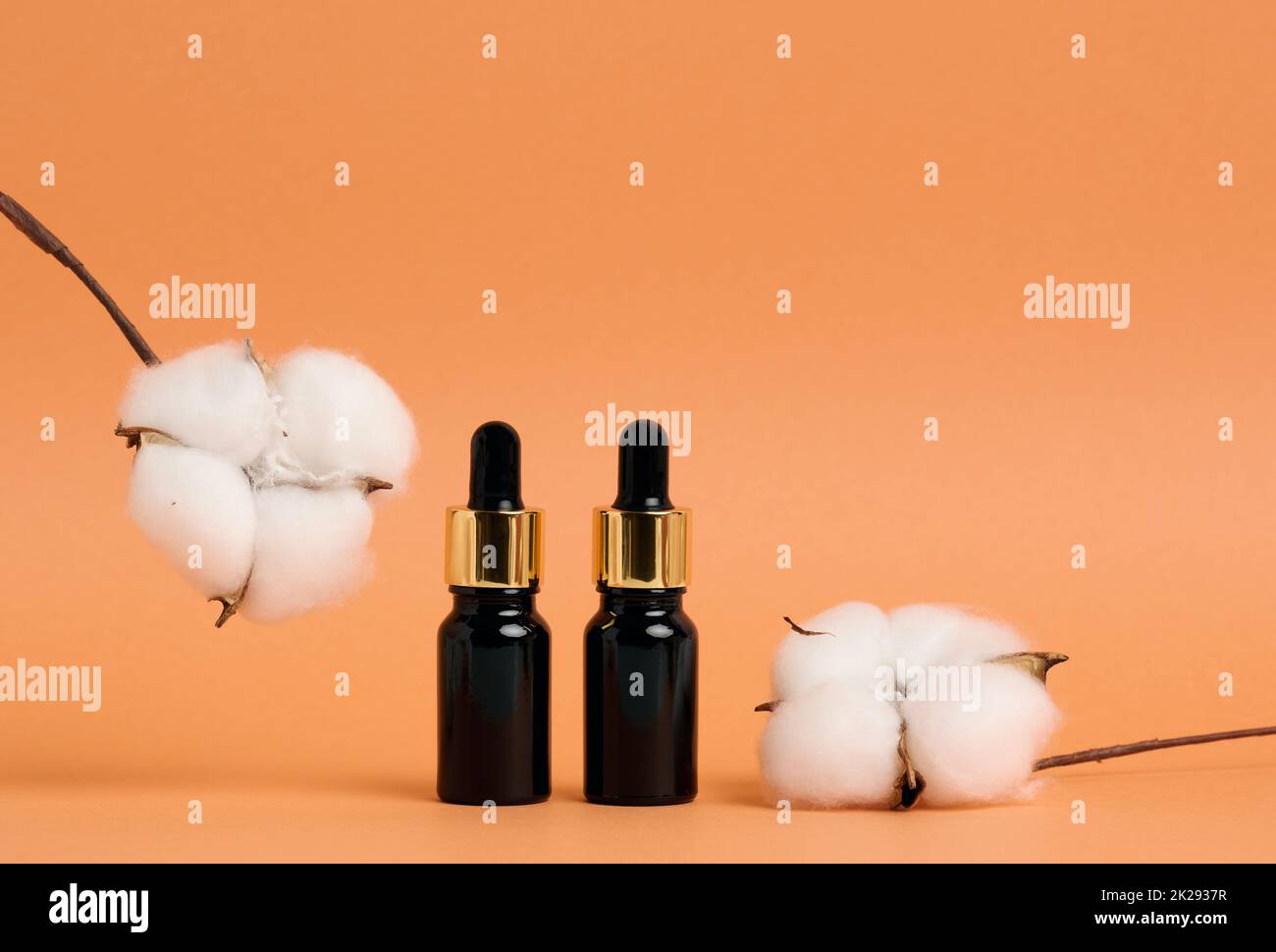 black glass bottle with a dropper for cosmetics on an orange background ...