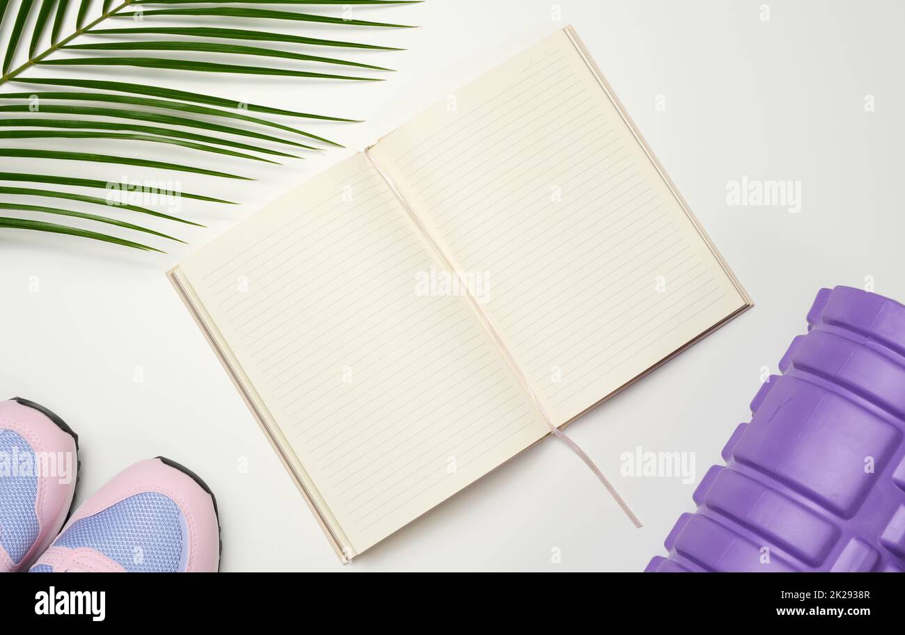 open blank notebook, a pair of sports gym shoes and dumbbells on a ...
