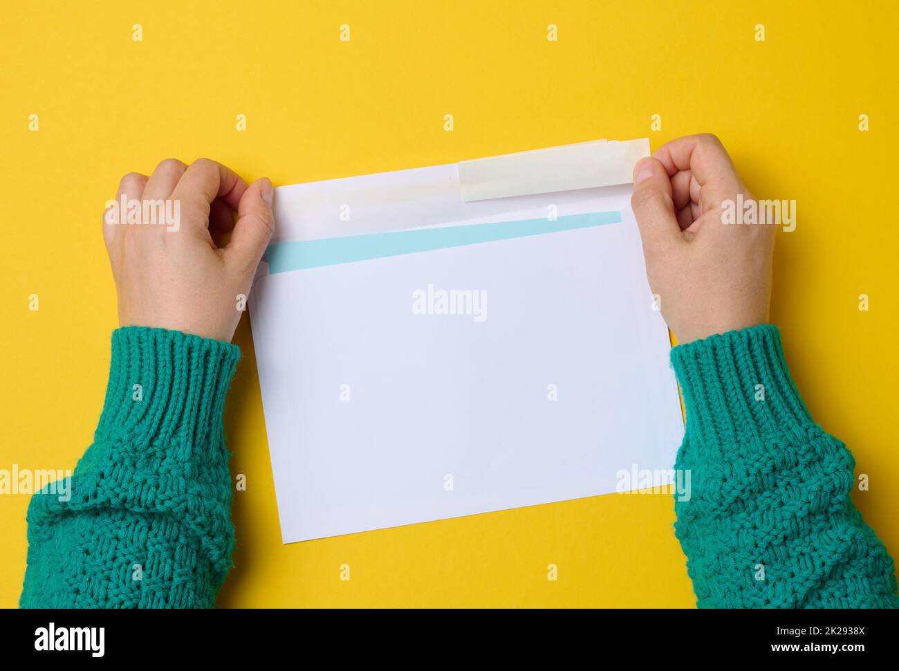 female hand holds white paper envelopes on an orange background, top ...
