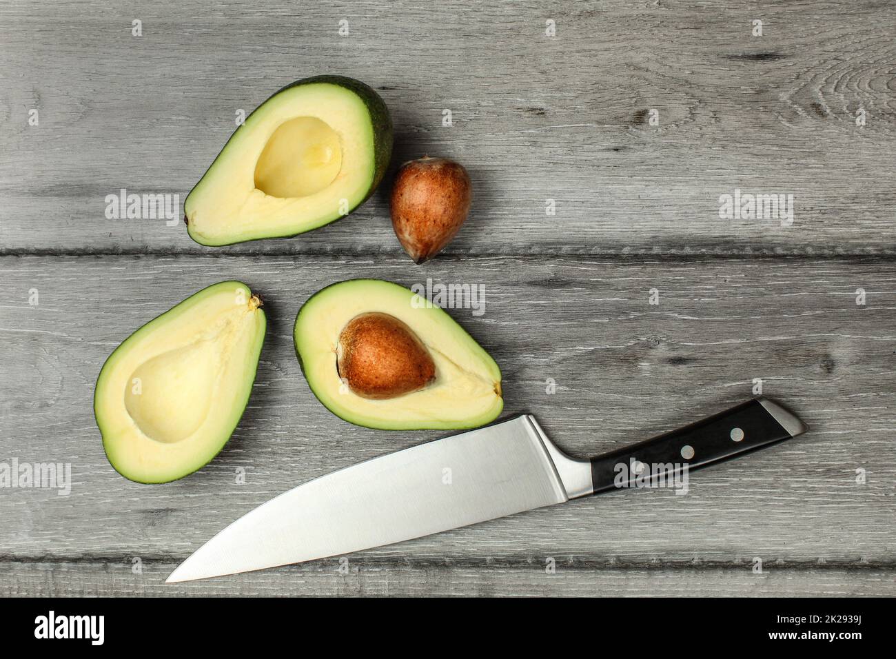 Tabletop view, two avocados cut in half, seeds visible, with chef's ...