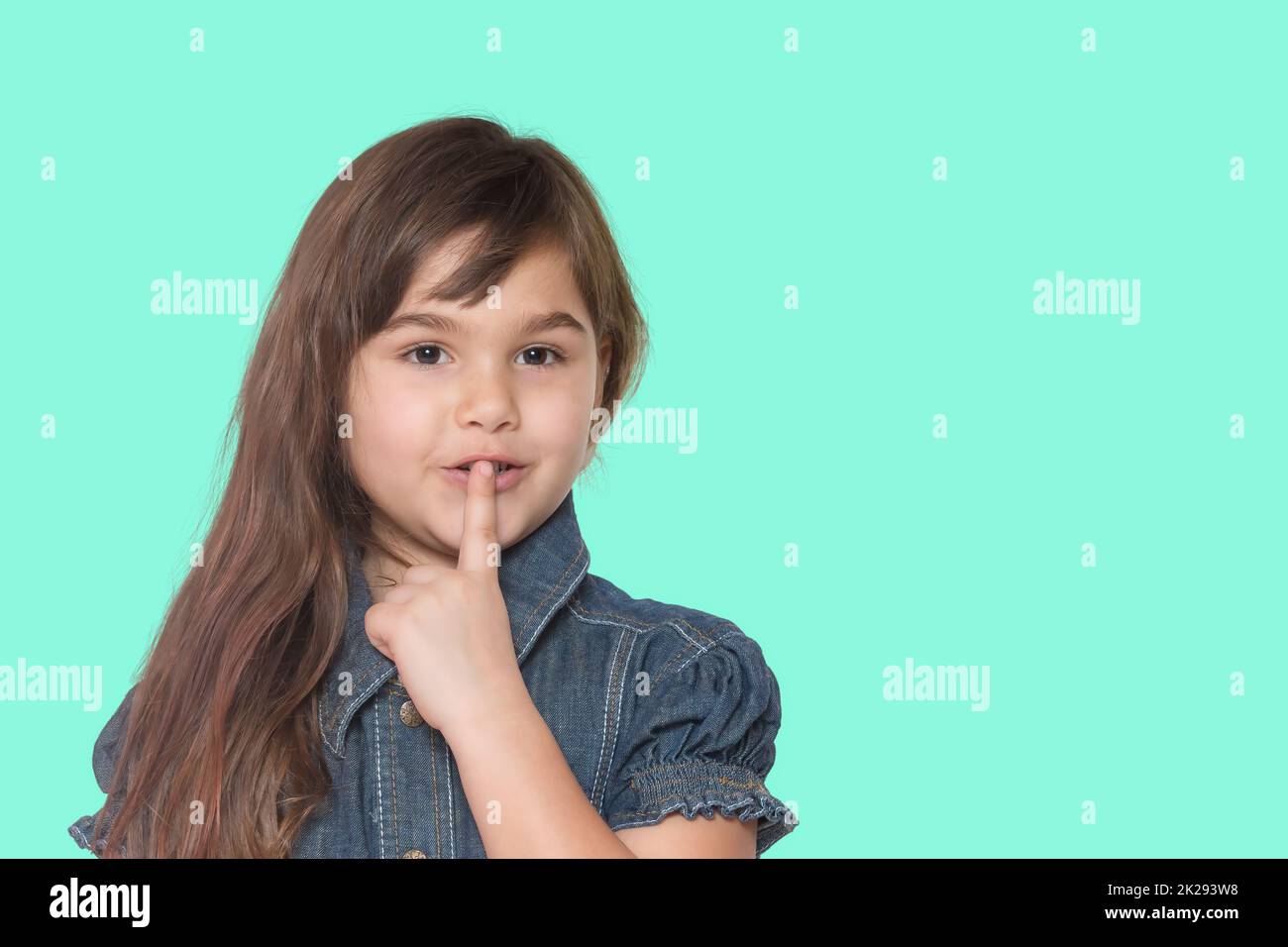 Tanned long haired little girl is putting finger up to lips Stock Photo ...