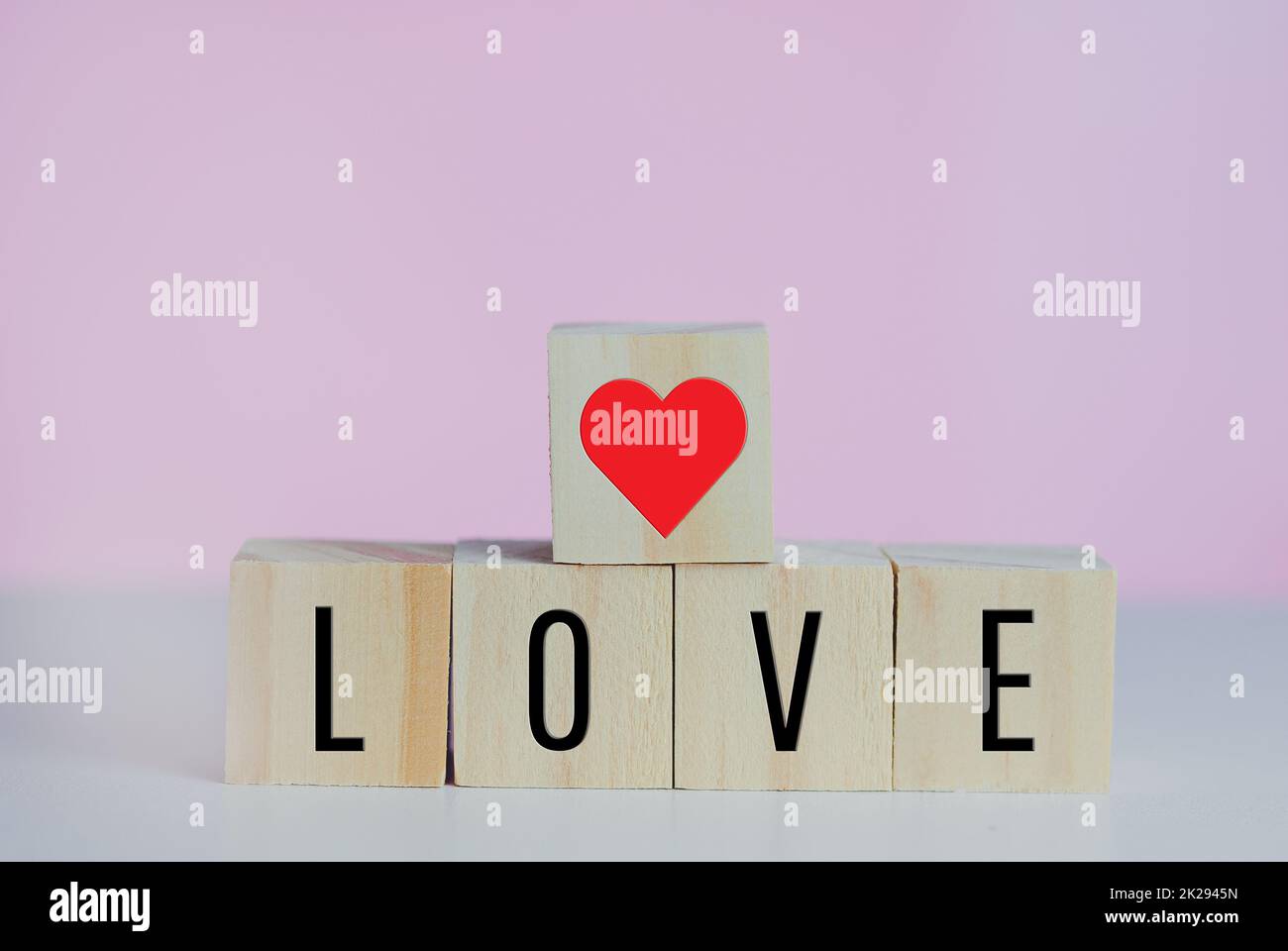 Wooden cubes with love symbol heart on the pink background and copy ...