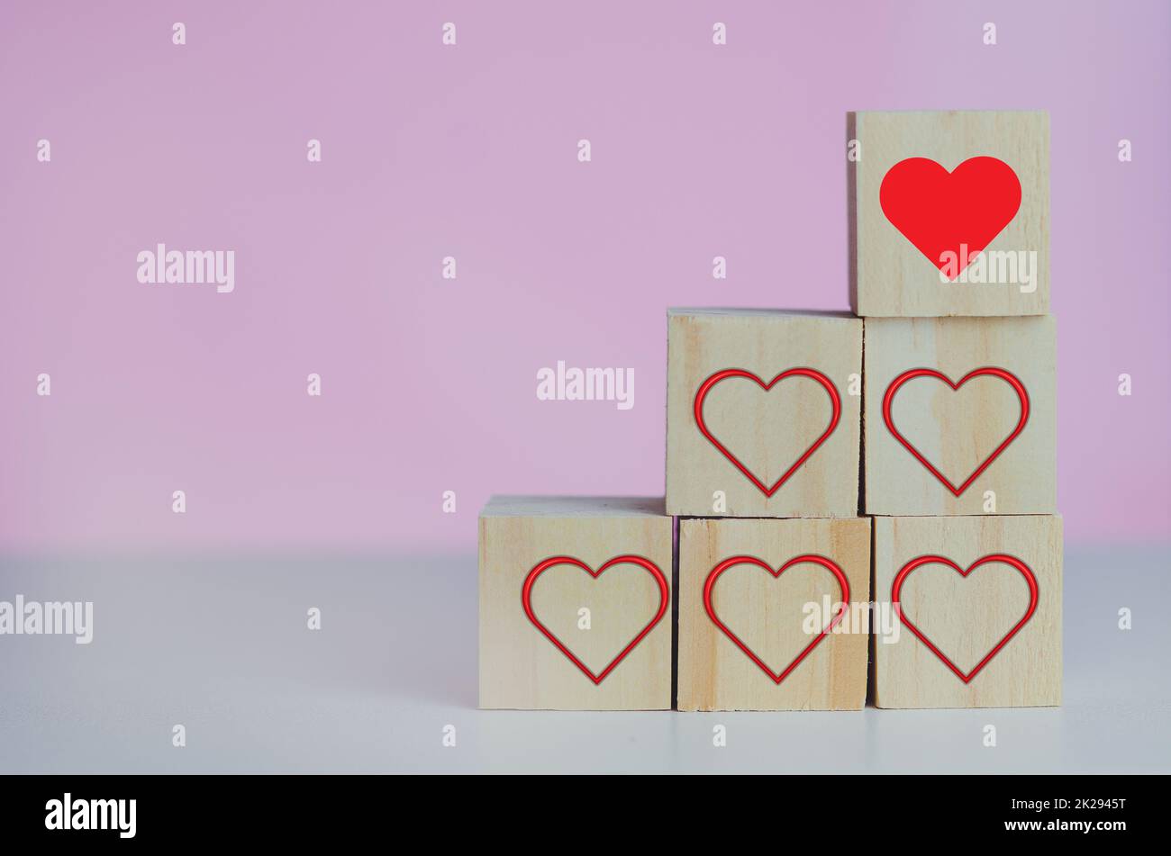 Wooden cubes with love symbol heart red on the pink background and copy ...