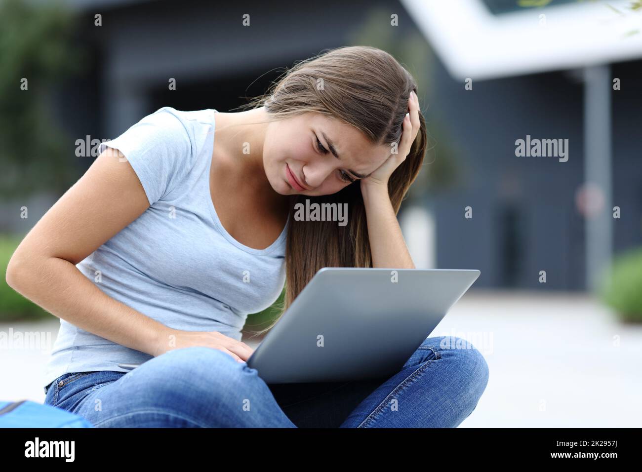 Sad teenage female checking laptop in the street Stock Photo - Alamy