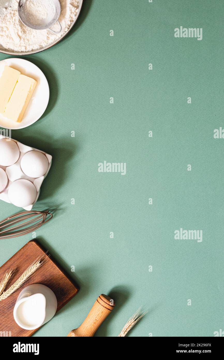Frame of food ingredients for baking on a green pastel background ...