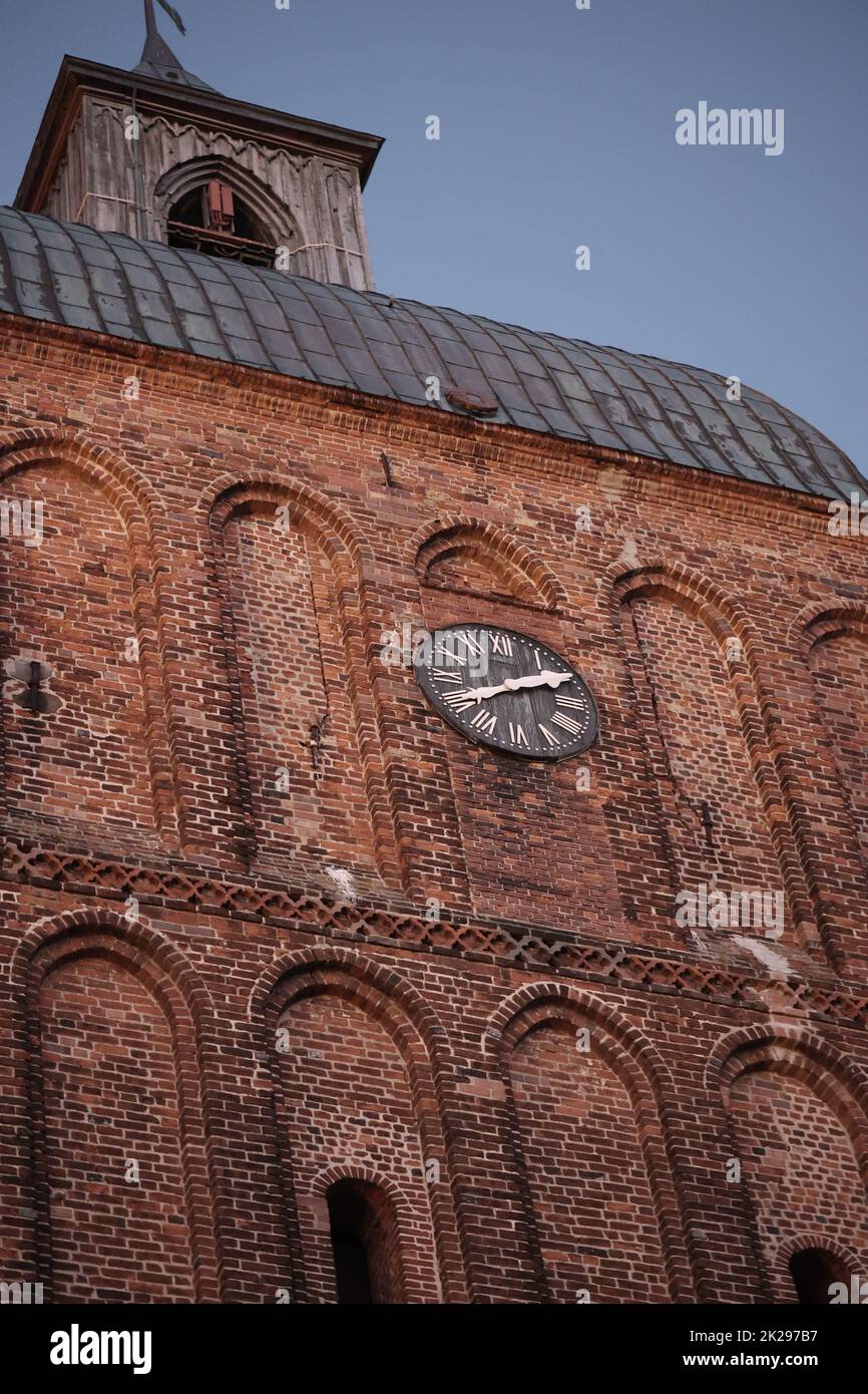 A tower clock is emblazoned on a large brick church building Stock ...