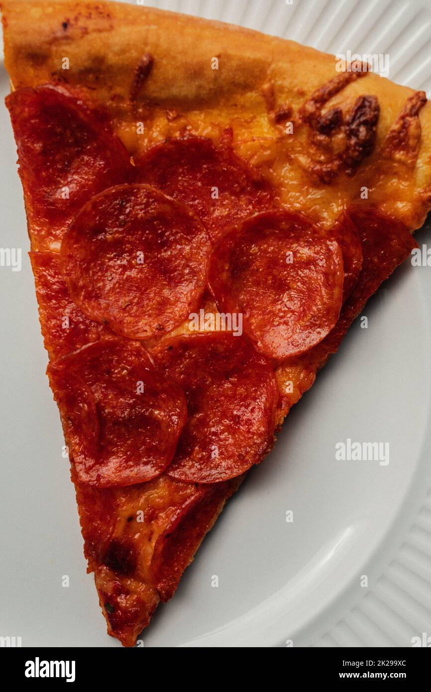 single slice of pepperoni pizza on white ceramic plate that looks like ...