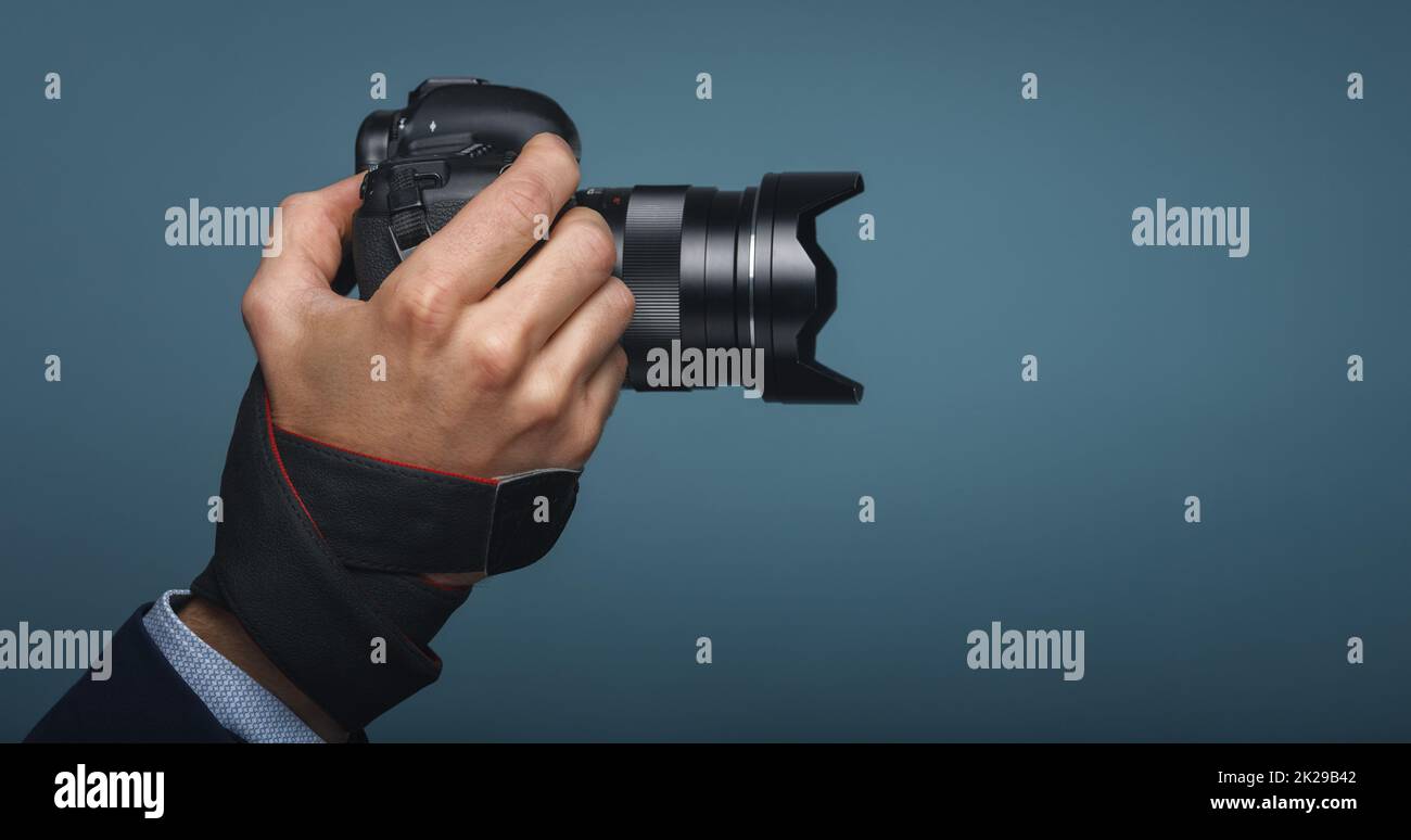 Photographer hand holding dslr camera on blue modern backround Stock ...