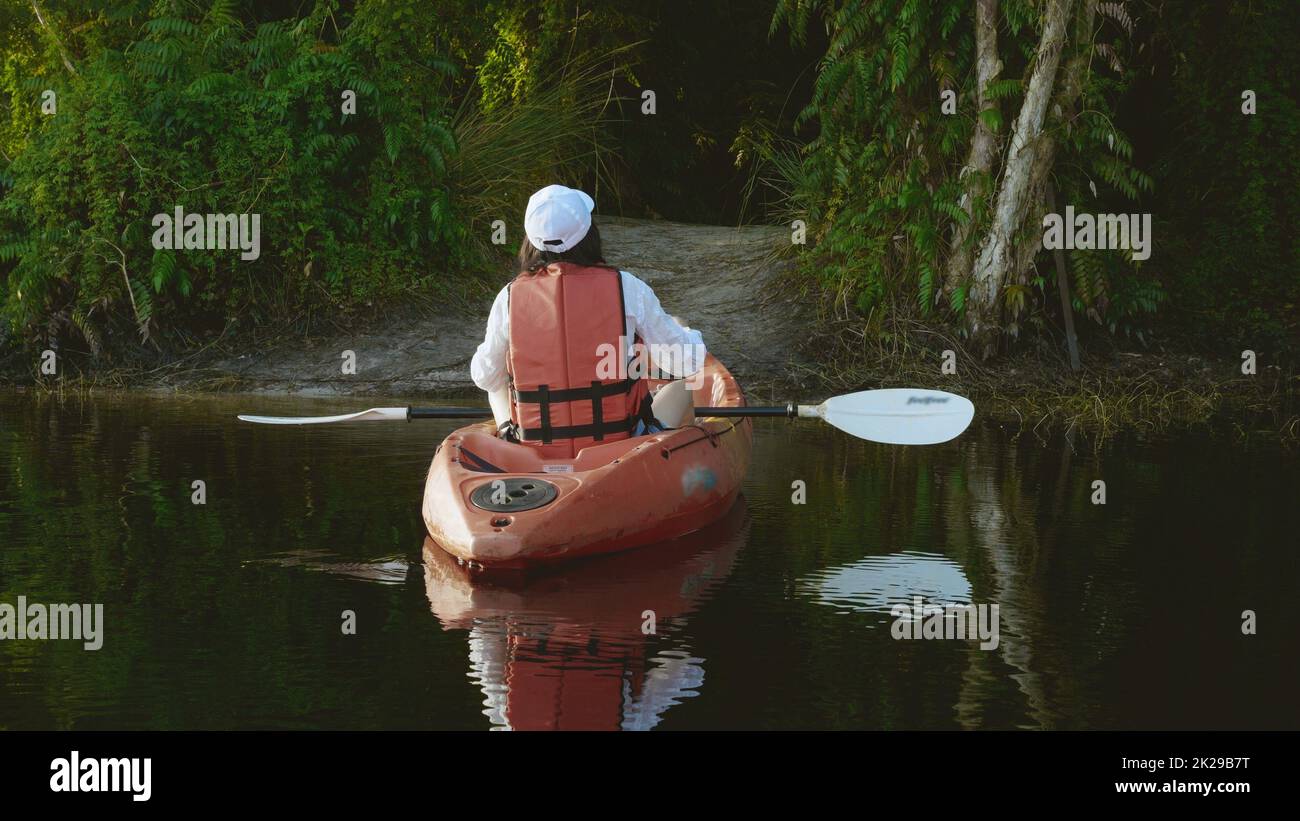 Back young adult woman paddling kayaking canoe on a lake on summer day ...