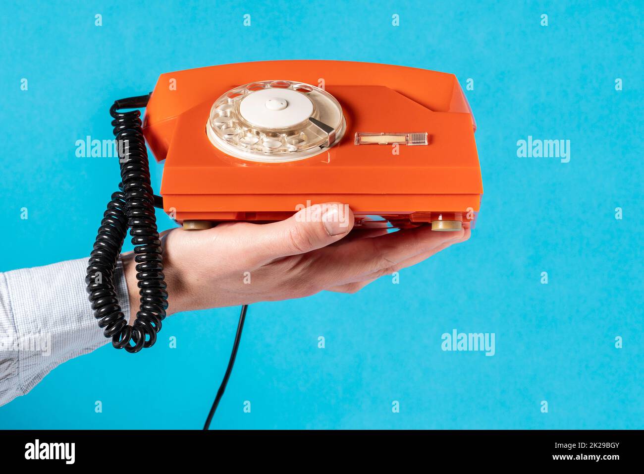 Hand with old rotary telephone over blue background Stock Photo - Alamy