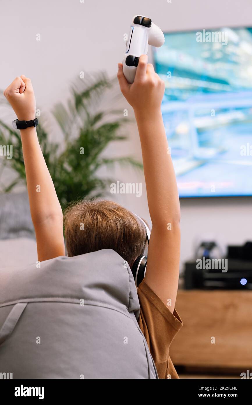 Teenager boy with joystick in his hands rejoices in victory in video ...