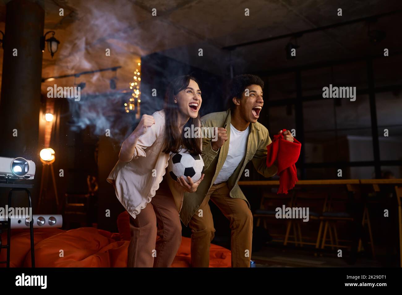 Couple watching football match on home projector Stock Photo - Alamy