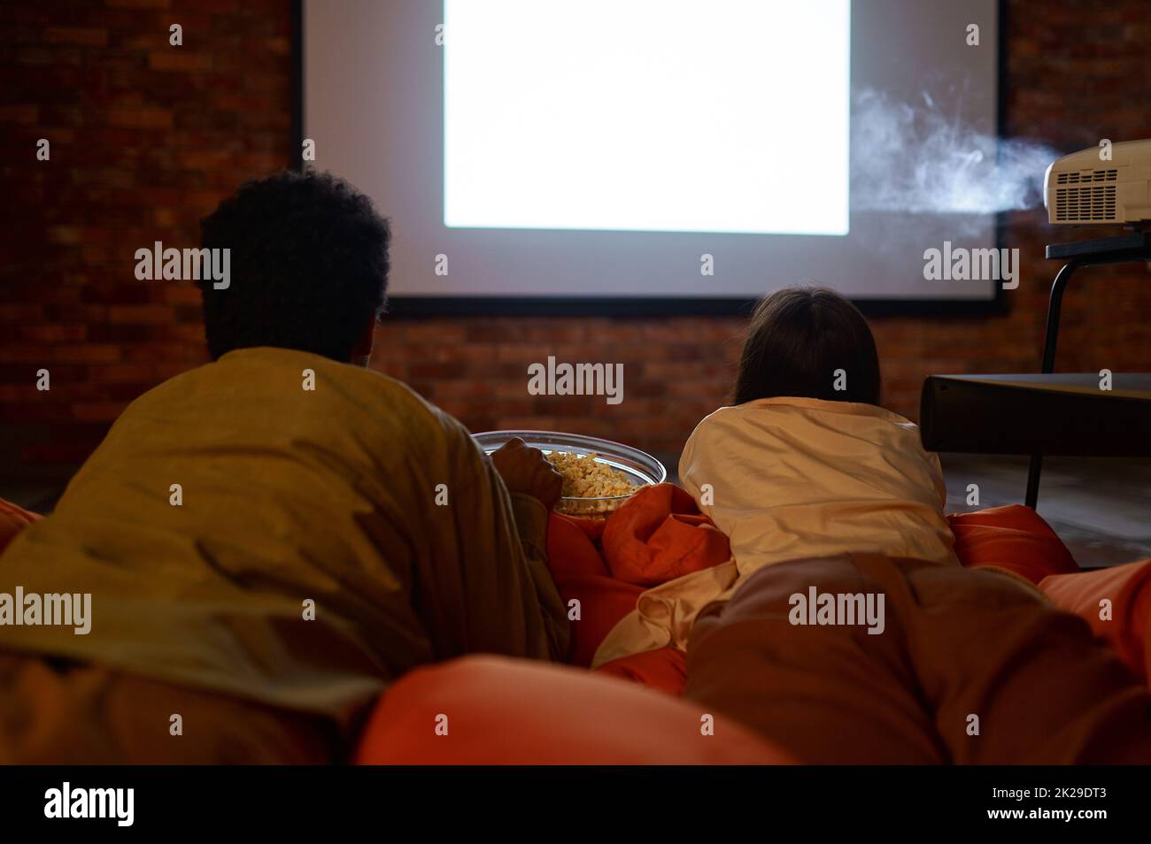 Couple lying on soft bag watching projector Stock Photo - Alamy