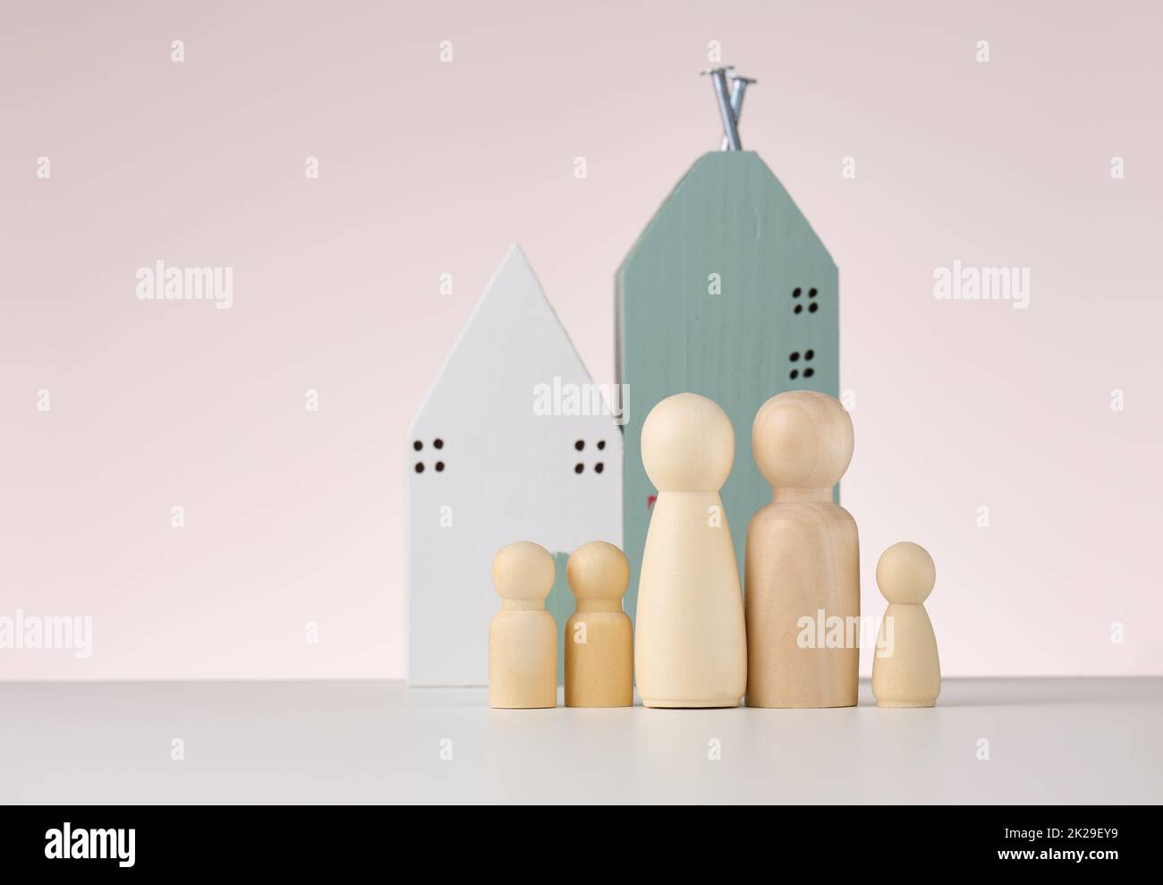 wooden figures of men and a miniature house on a beige background. The ...