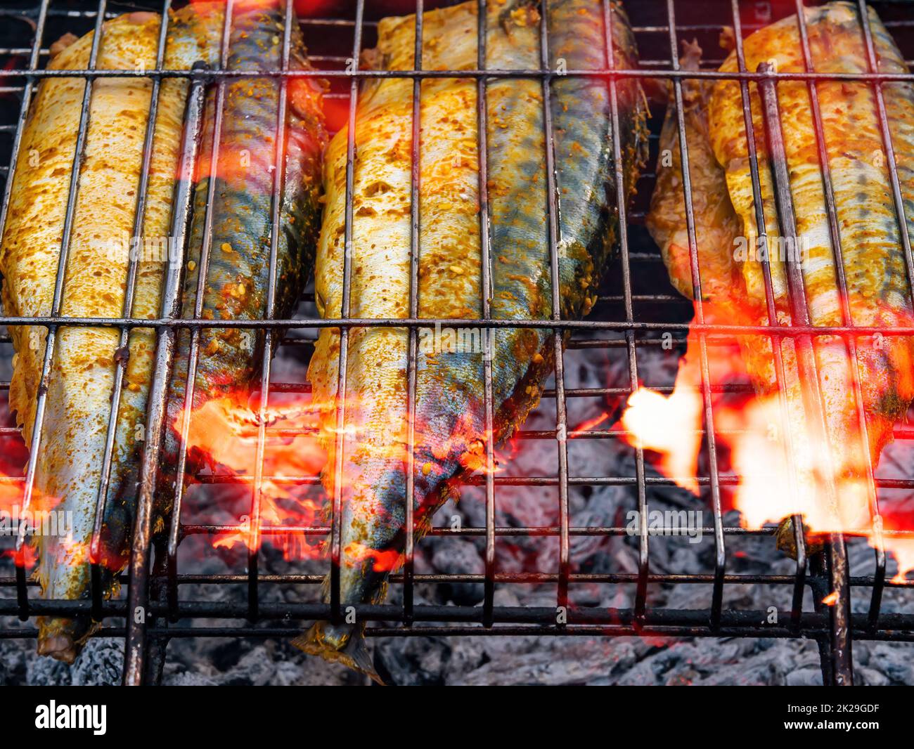 Mackerel fish is baked on a metal grill in a flame of fire Stock Photo ...