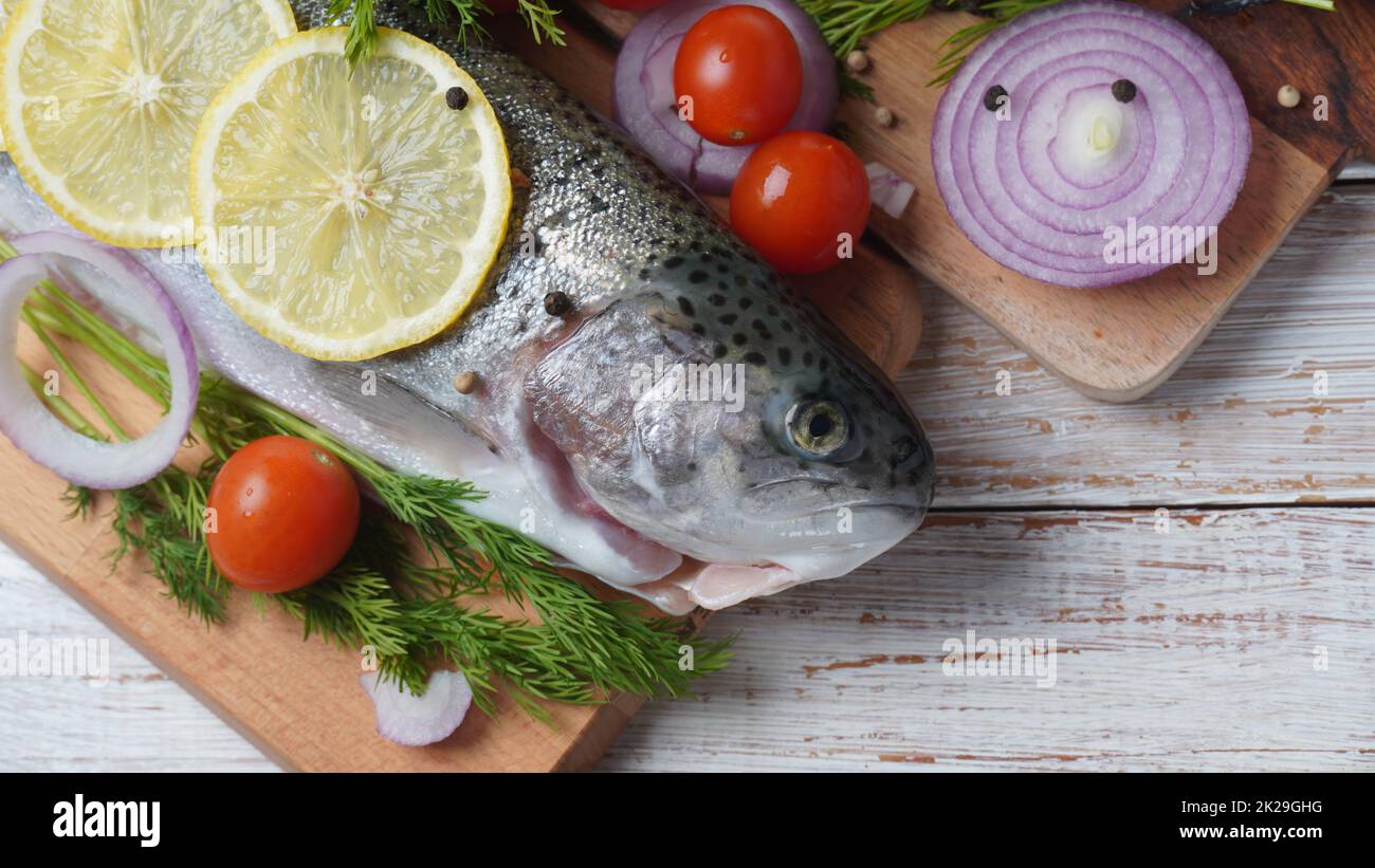 Fresh trout on a table with lemon, pepper and dill. Tasty fish ready ...