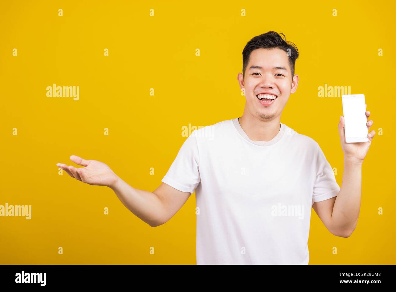 Asian handsome young man smiling positive showing mobile phone blank ...