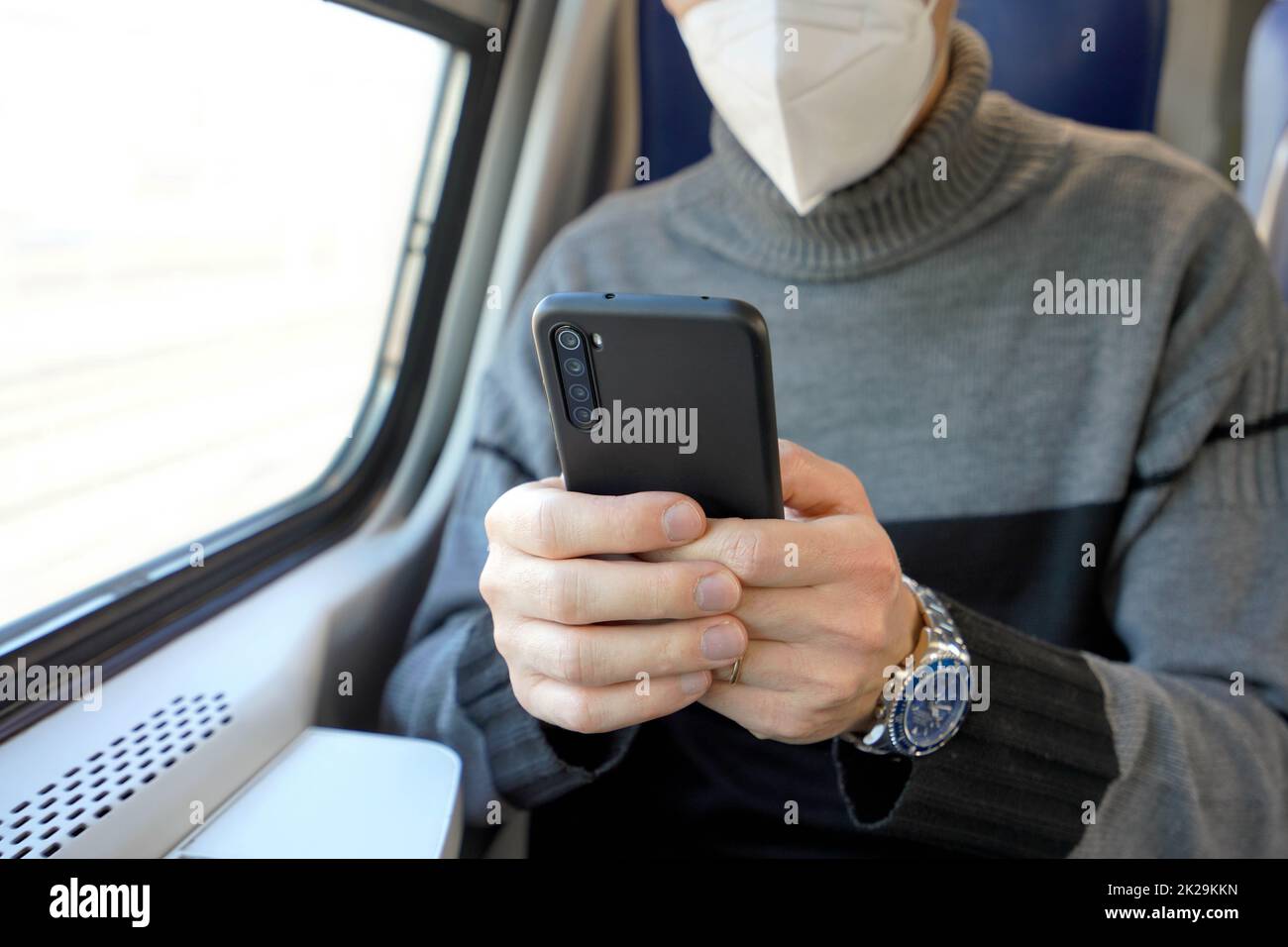 Man on public transport using mobile app wearing medical face mask ...