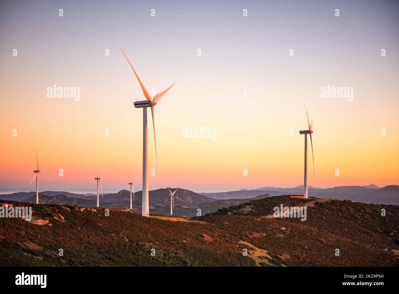 Turbines in a mountain wind farm at sunset. Ecological energy ...