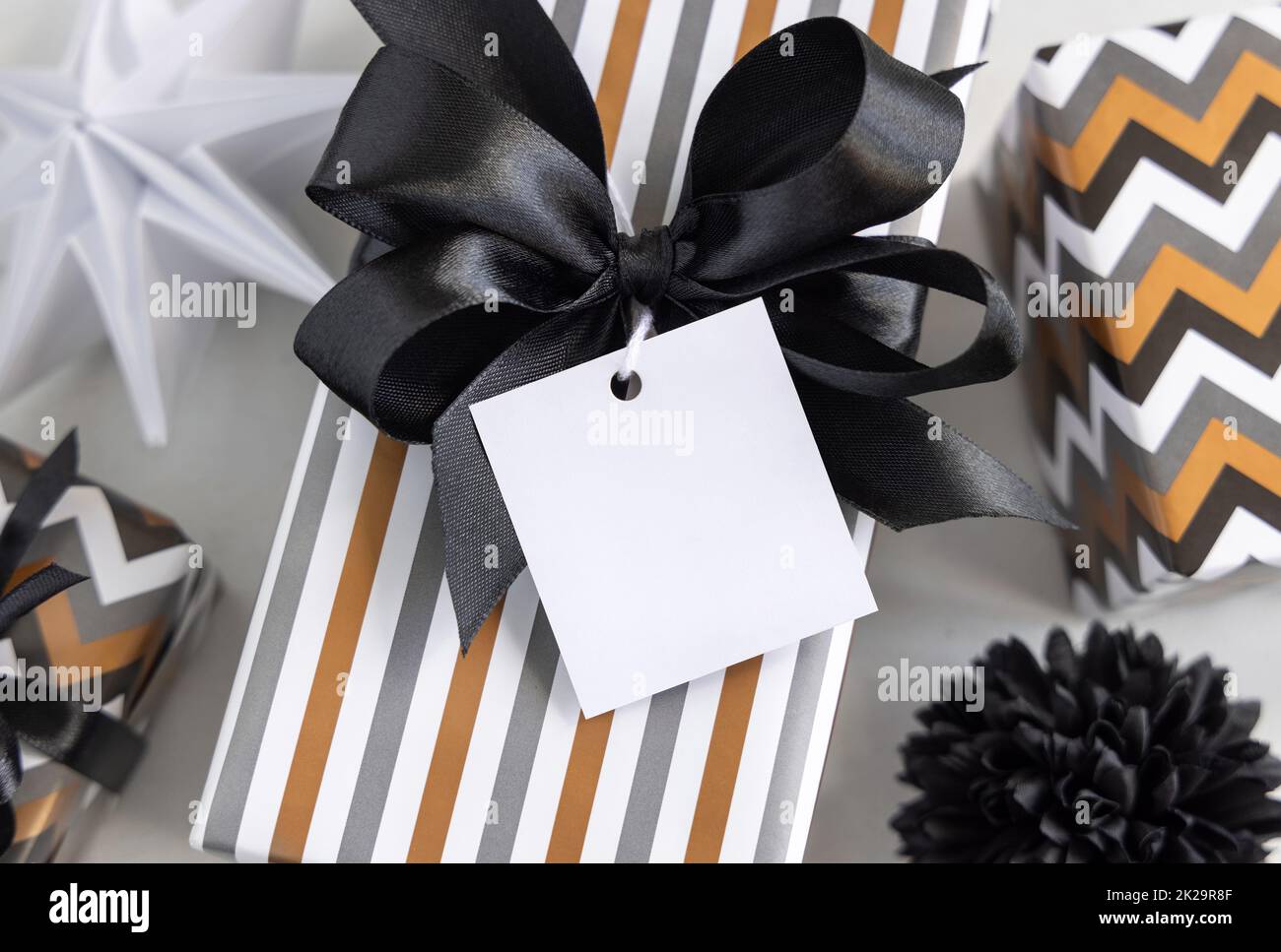 Wrapped present with blank square gift tag and black bow close up ...