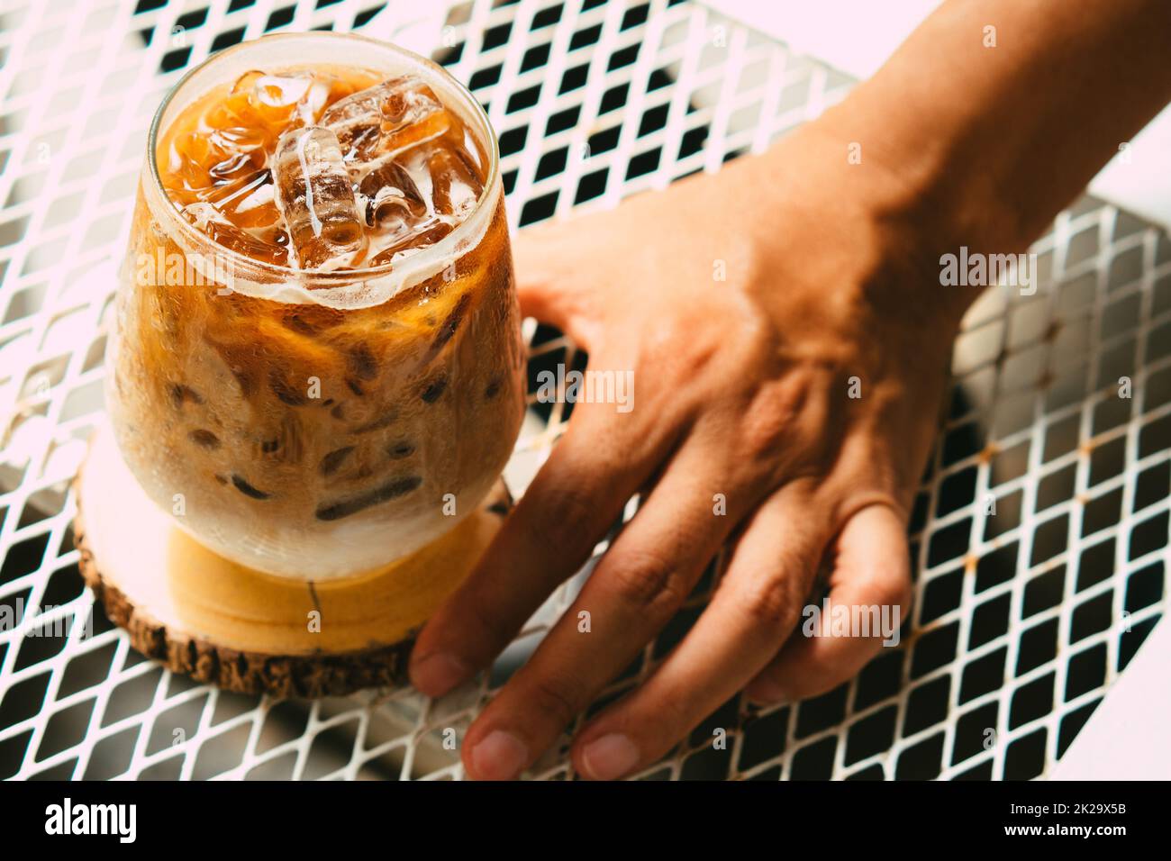 Hand hold iced latte coffee in a glass with cream on bottom . cold ...