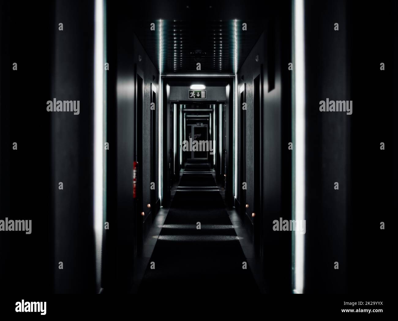 A low-key shot with a shallow depth of field of a black hotel corridor ...