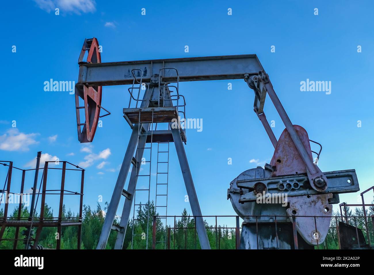 An abandoned oil or gas rocking machine against a blue sky, exhausted ...