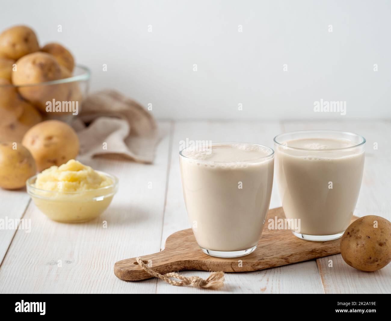 Potato milk pouring into glass on white wooden bg Stock Photo - Alamy