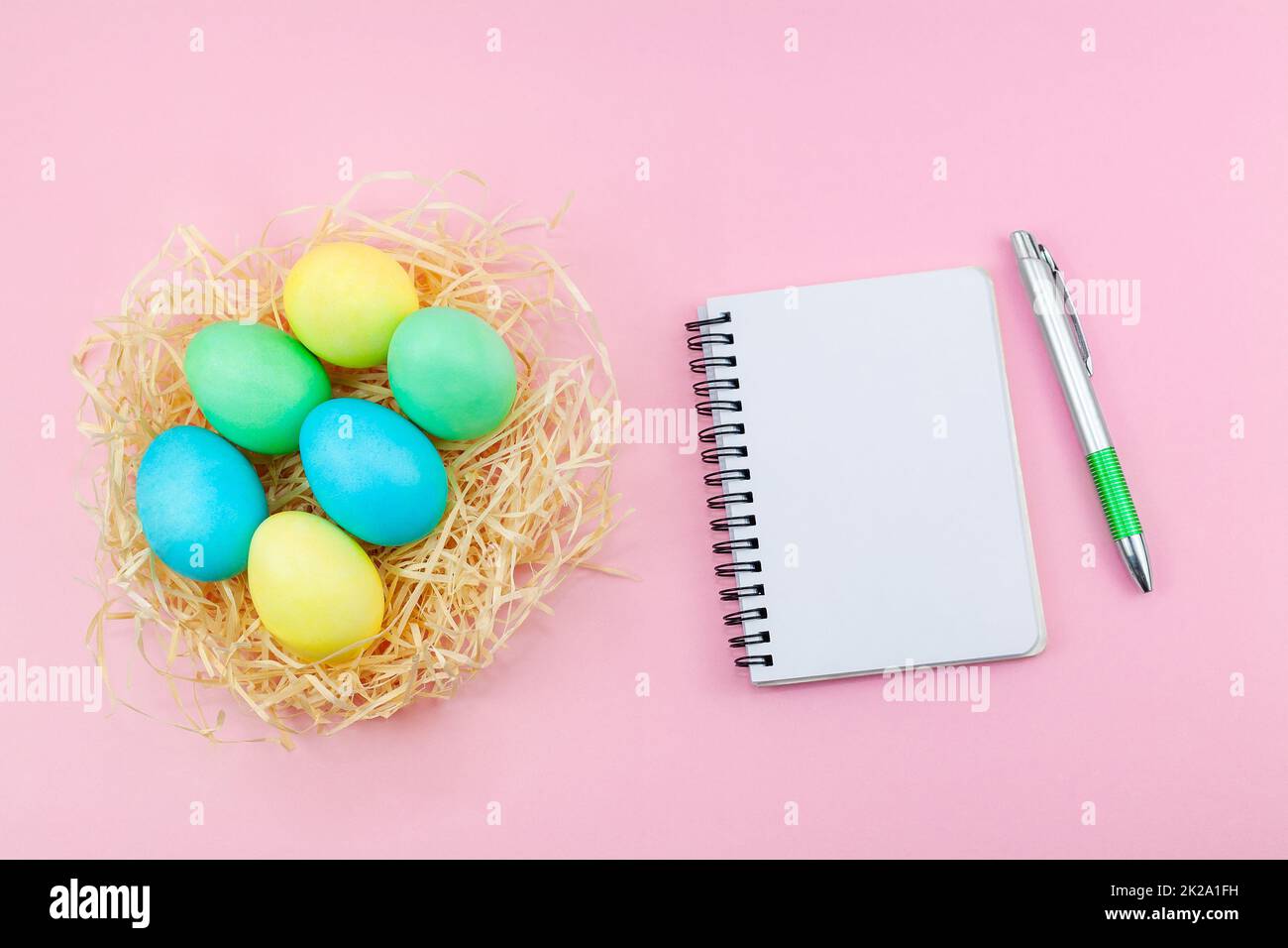Blank notepad and pen on trendy dark pink background. Easter eggs ...