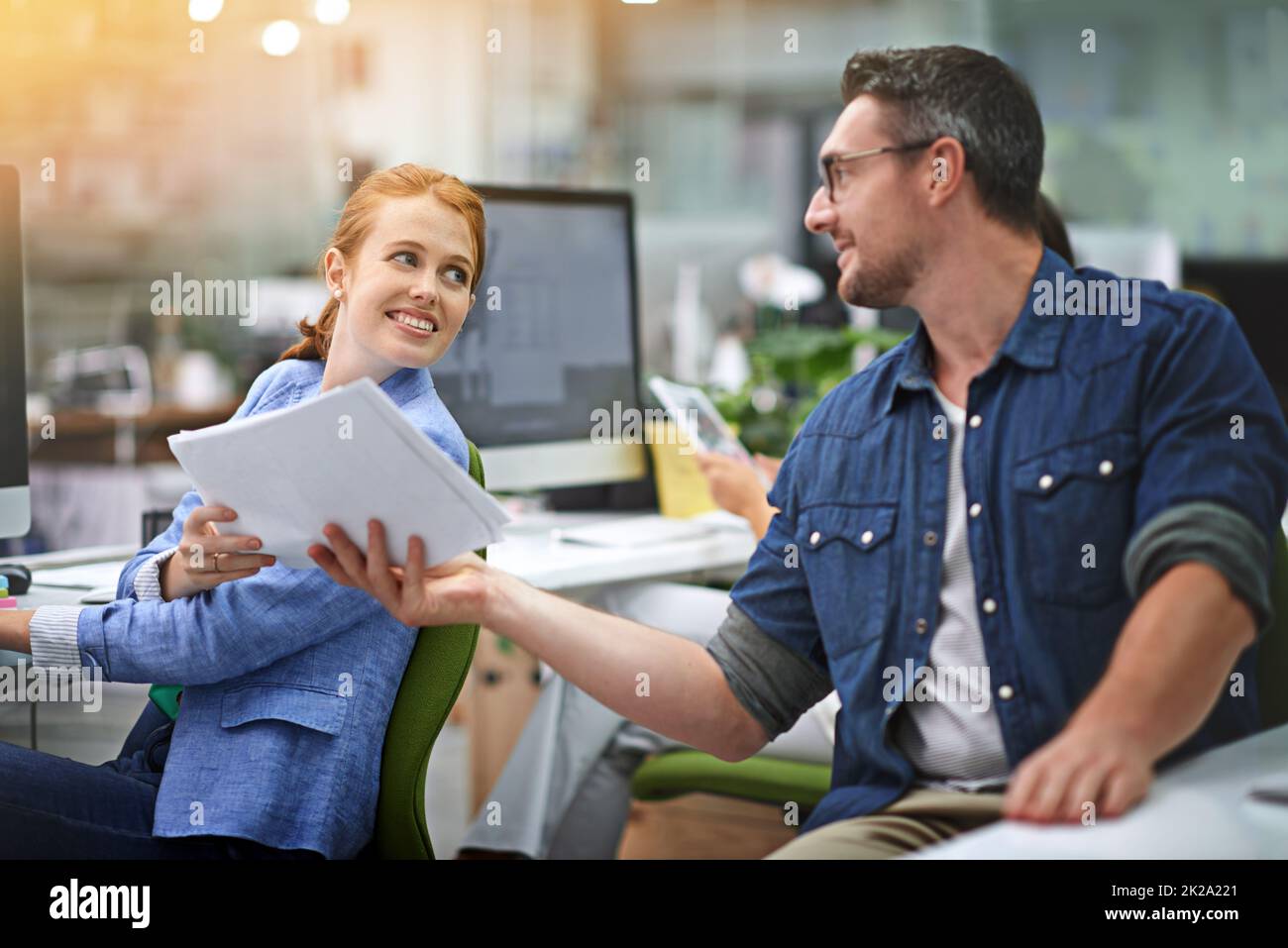 Here we go...a young businesswoman handing some paperwork to a male ...